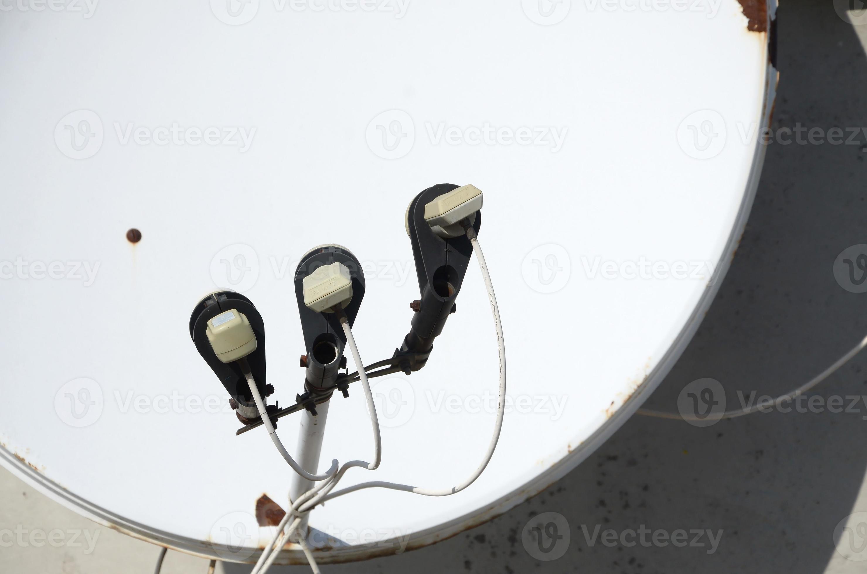 White satellite dish with three converters mounted on residental ...