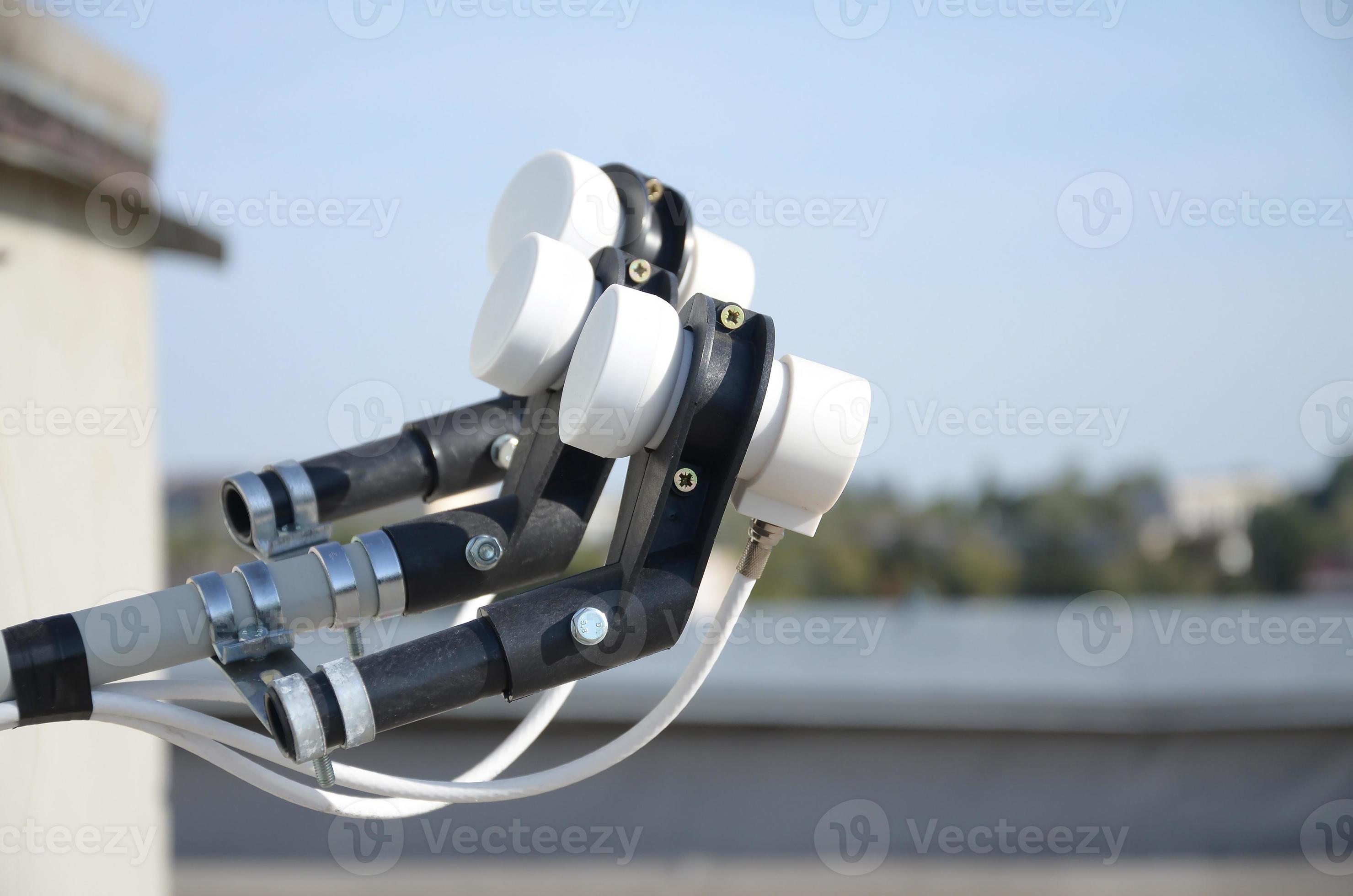 White satellite dish with three converters mounted on residental ...