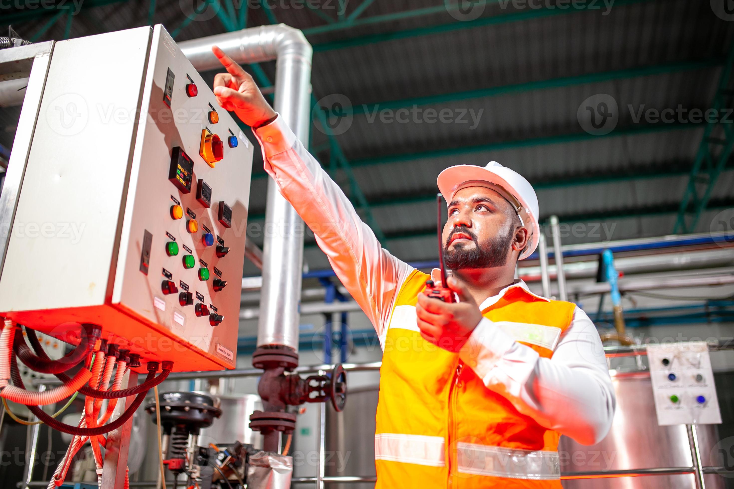 Professional engineers with helmets work to maintain industrial construction equipment, workers ...