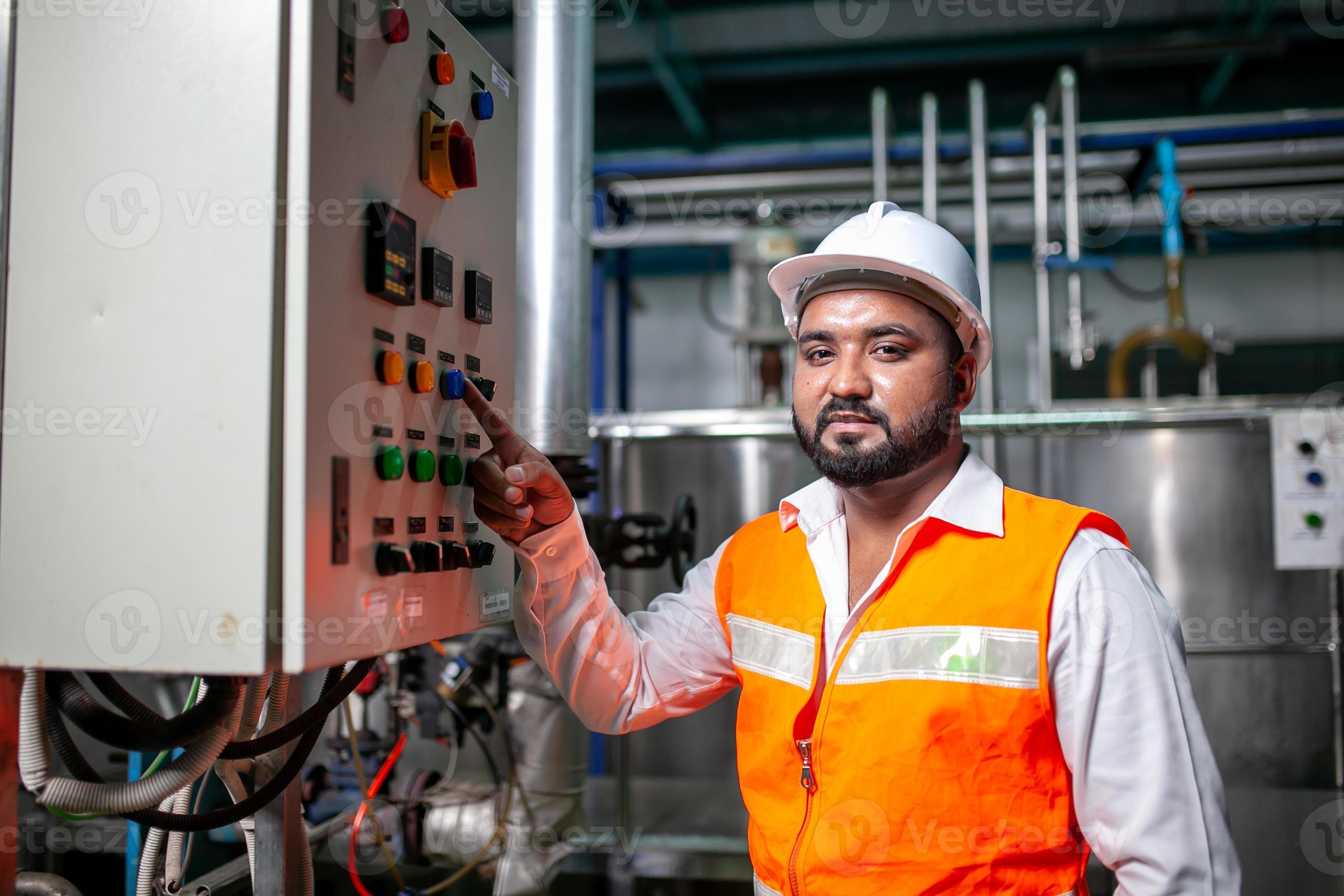 Professional engineer with helmet works to maintain industrial construction equipment. Worker is ...