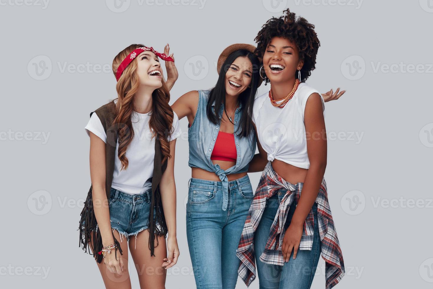 Three attractive stylish young women laughing while standing against ... Three attractive stylish young women laughing while standing against ...