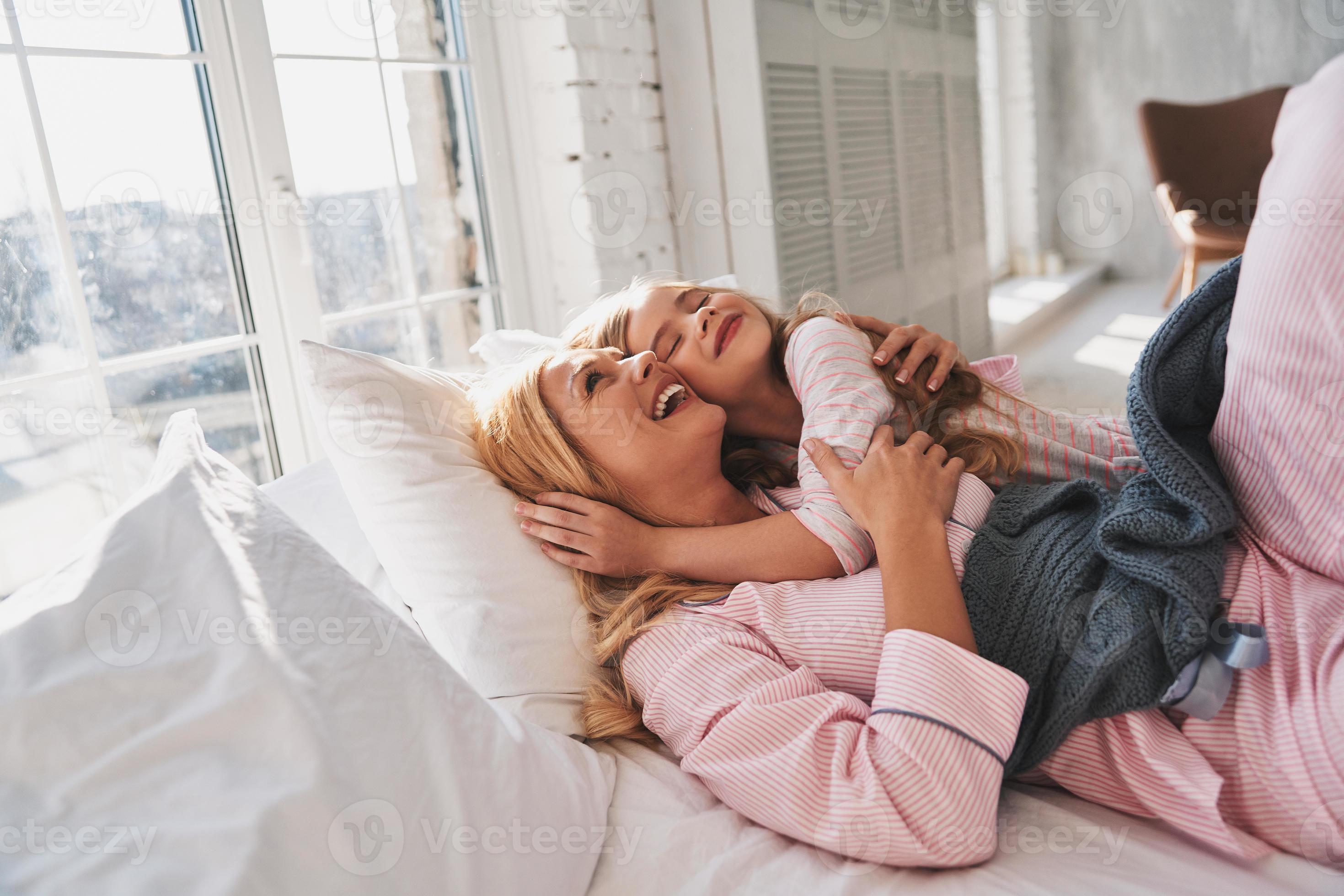 Family is everything. Young beautiful mother with her cute little daughter smiling while lying ...
