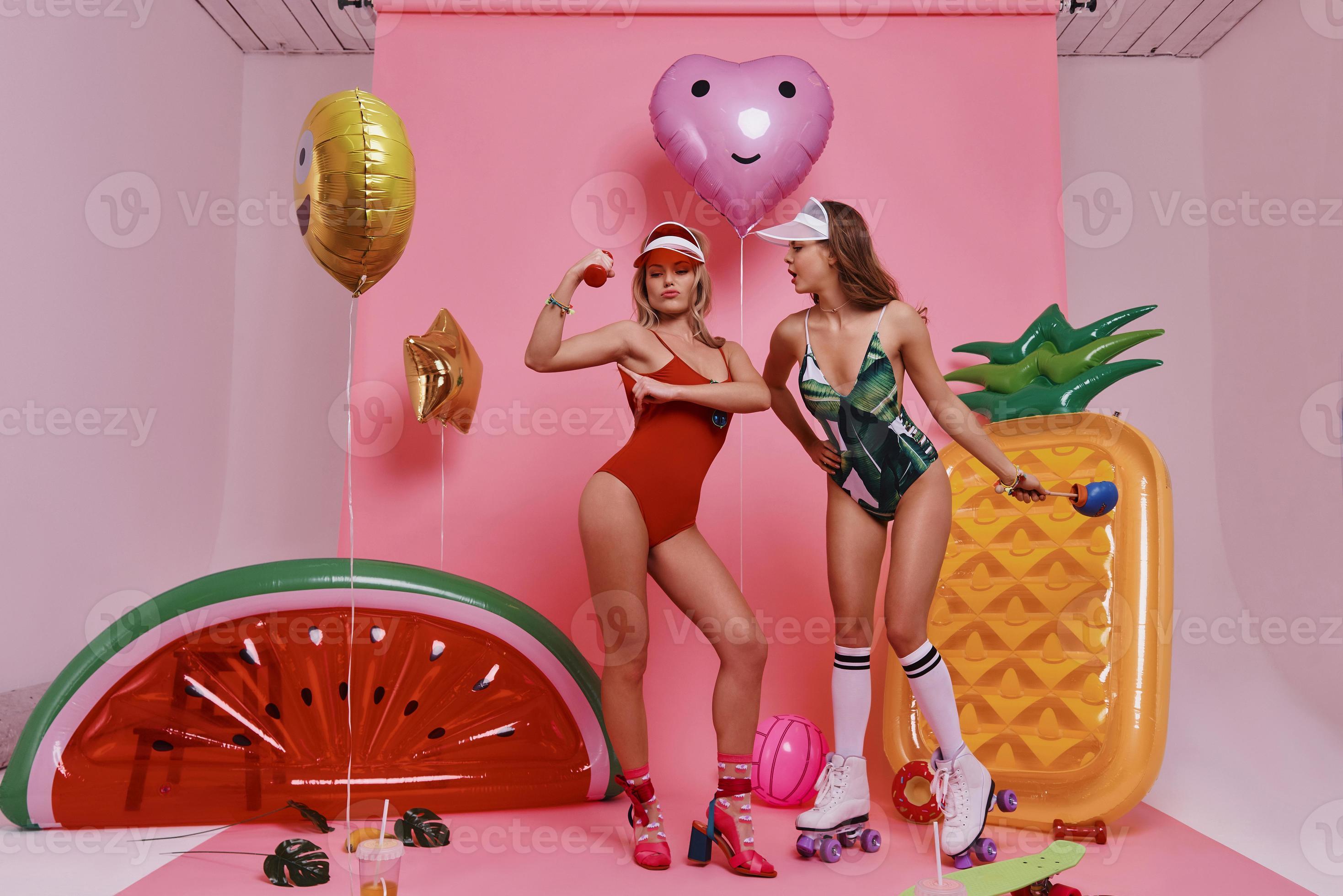 On the way to perfect shape. Full length of two playful young women in swimwear exercising while ...