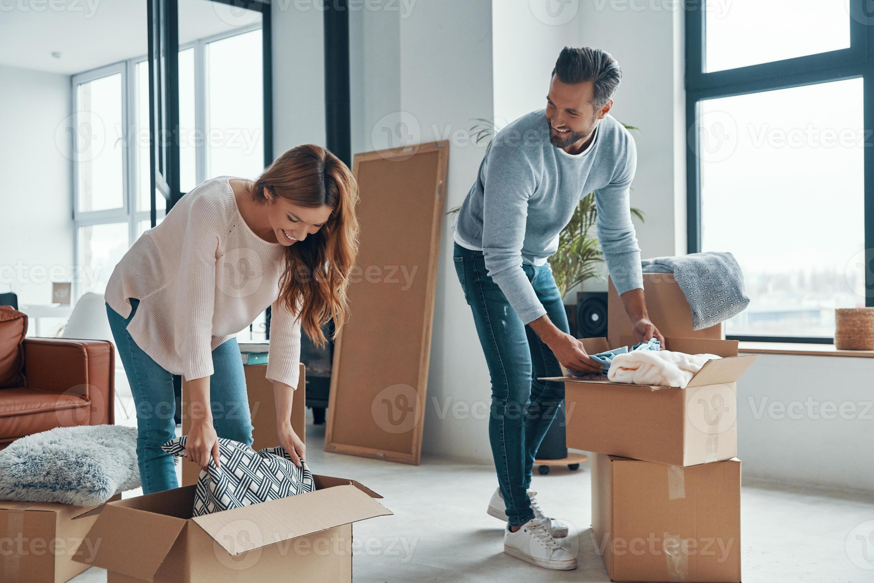 Py Young Couple Smiling And Unboxing Their Stuff While Moving Into A