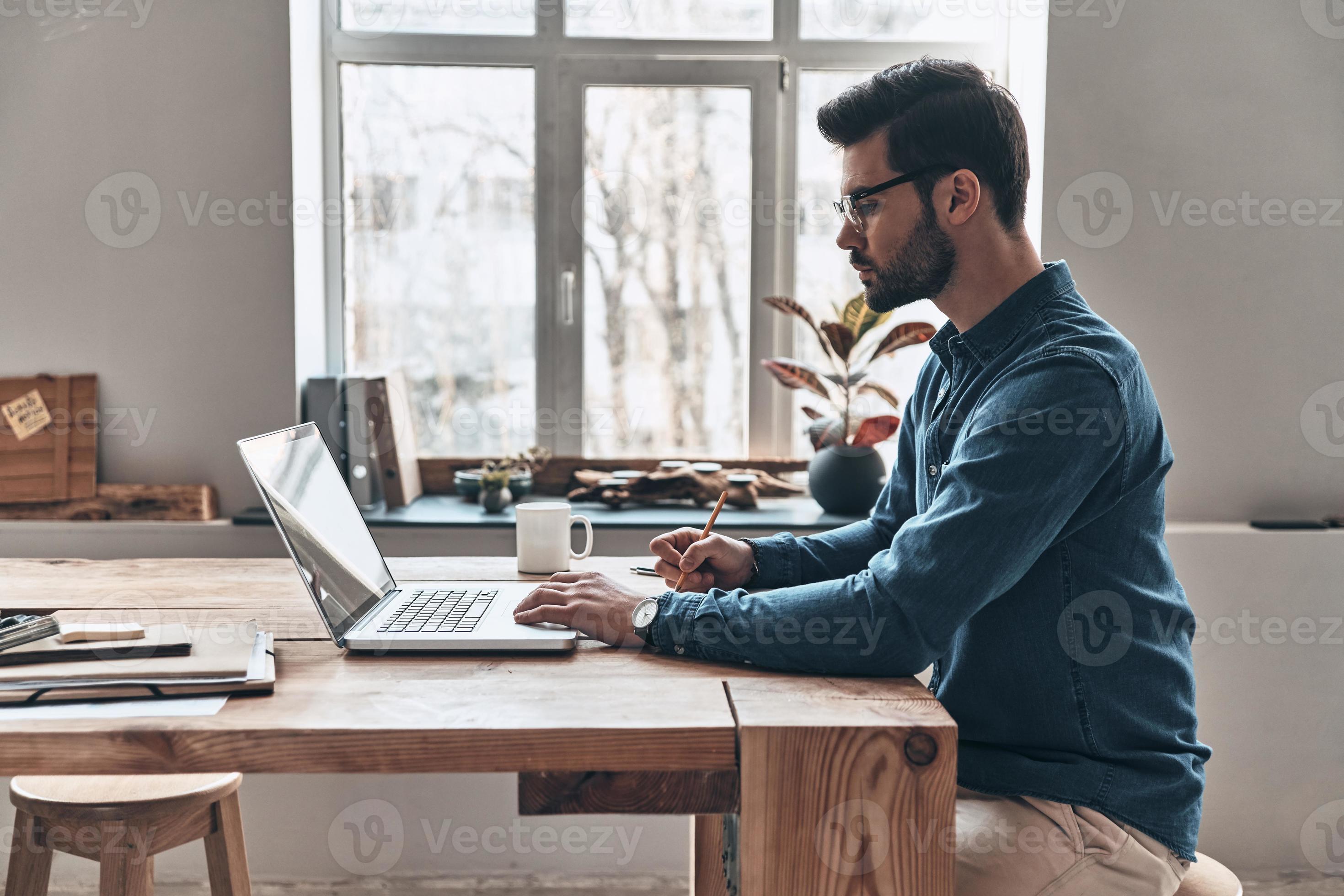 Developing new project. Side view of concentrated young man using ...