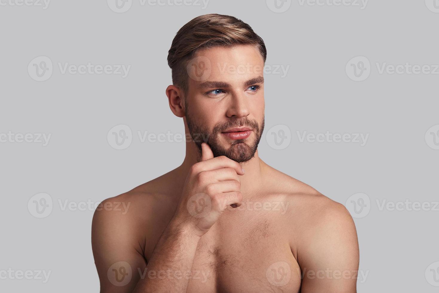 Pleasant dreams. Thoughtful young man looking away and keeping hand on ...