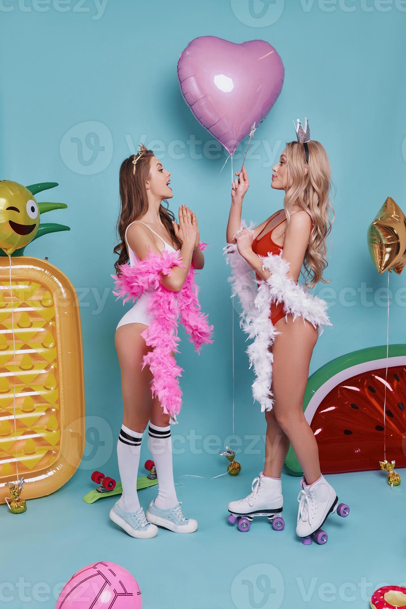 Putting a spell. Full length of two playful young women in swimwear playing with magic wand ...