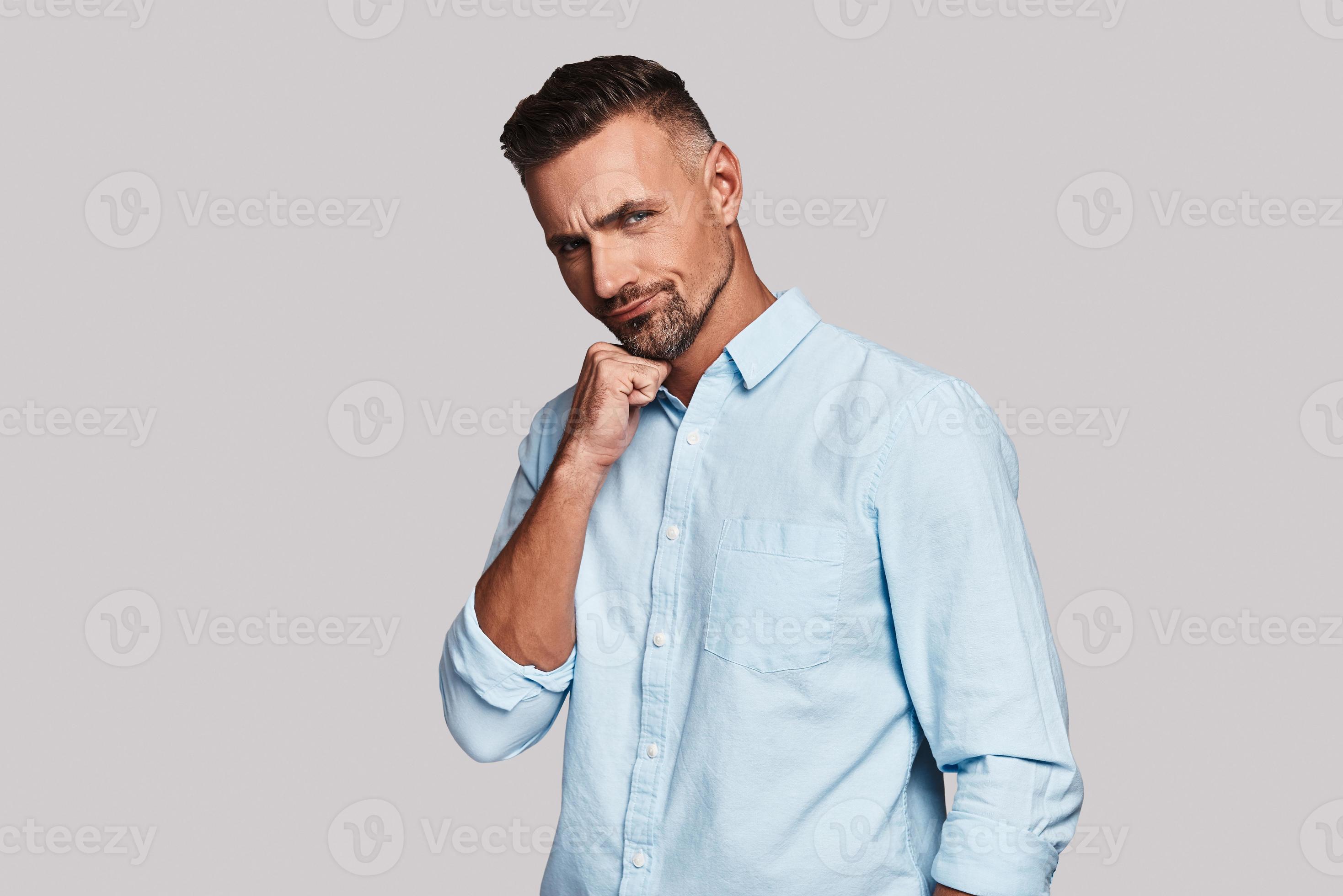 Thinking over things. Handsome young man keeping hand on chin and ...