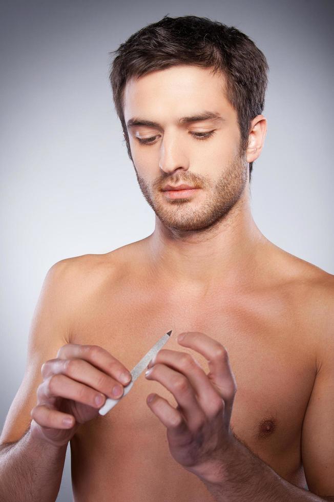 Everything should be perfect. Handsome young shirtless man polishing ...