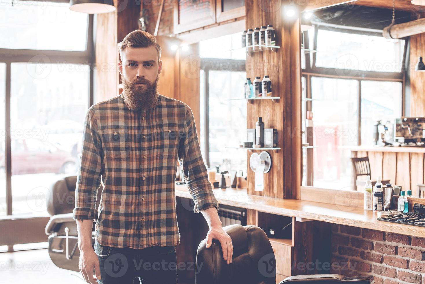 Confident barber expert. Young bearded man looking at camera and ... Confident barber expert. Young bearded man looking at camera and ...