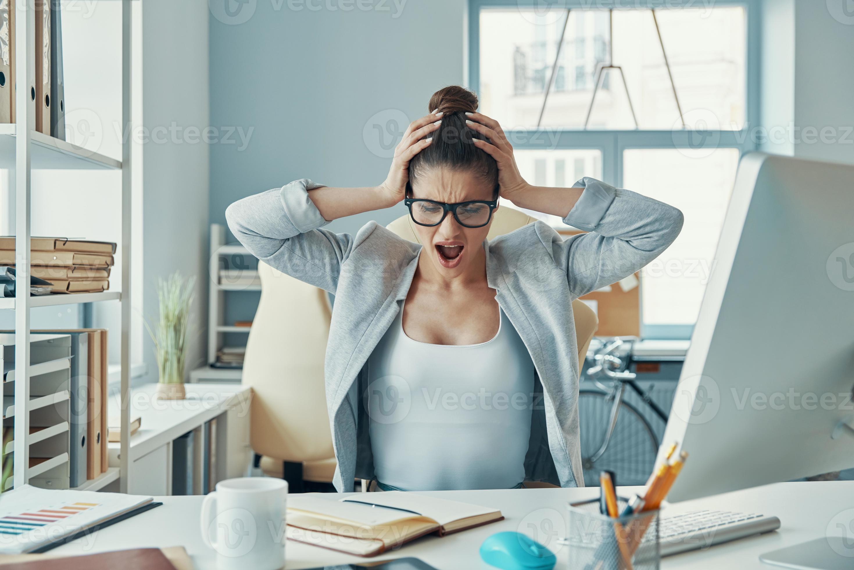 mujer joven estresada con ropa informal inteligente manteniendo la cabeza en las manos y ...