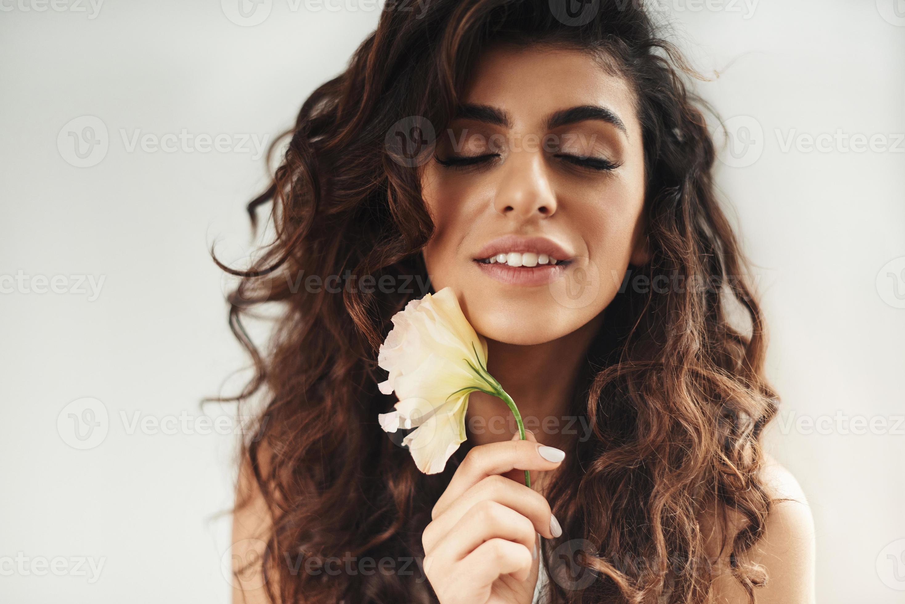 So Soft Attractive Young Woman Smiling And Keeping Eyes Closed While Standing Against Grey
