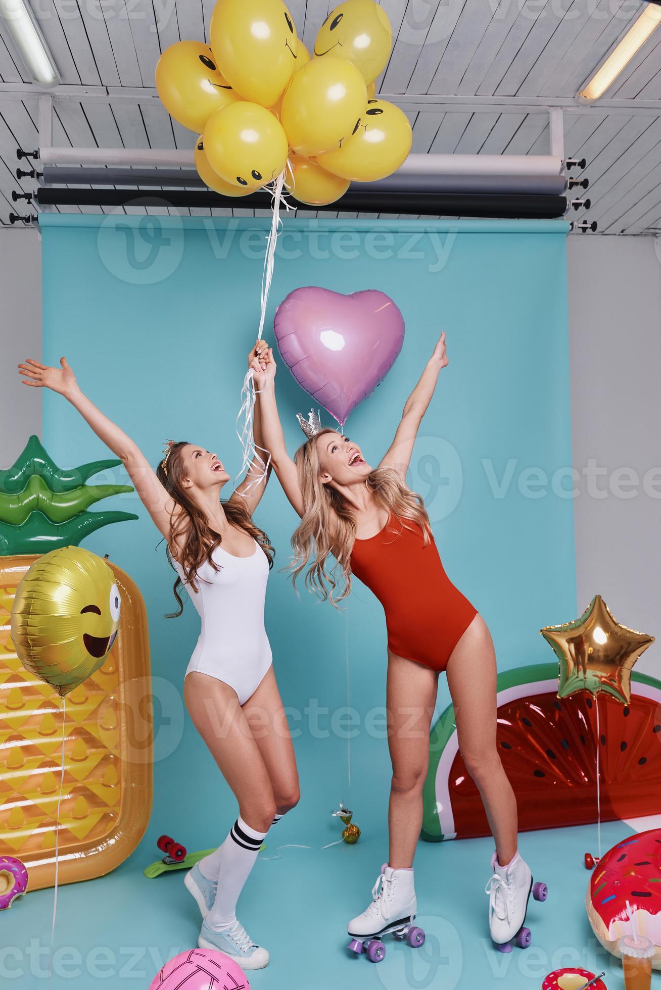 One more step and they will fly. Full length of two playful young women in swimwear holding ...