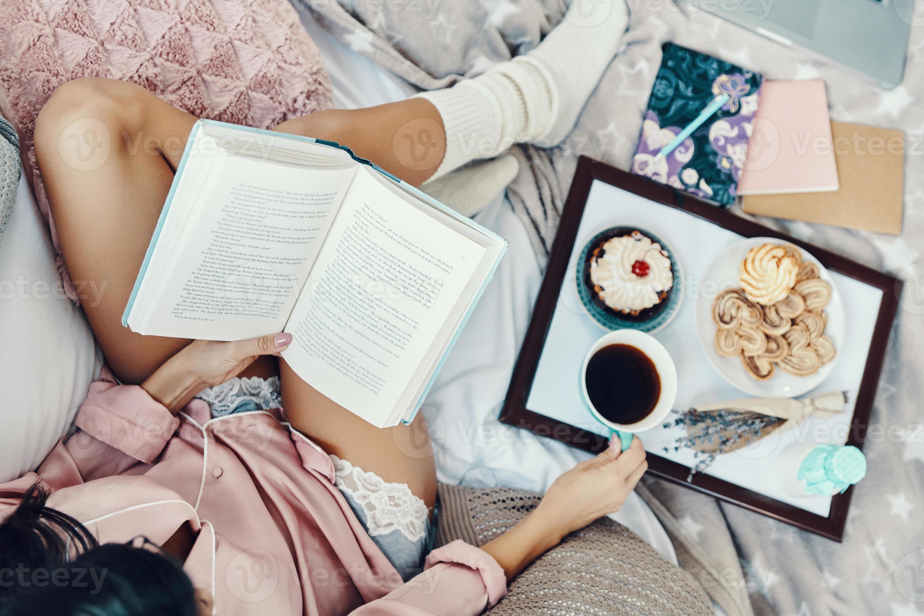 Top view of beautiful young woman in pajamas reading book and enjoying ... Top view of beautiful young woman in pajamas reading book and enjoying ...