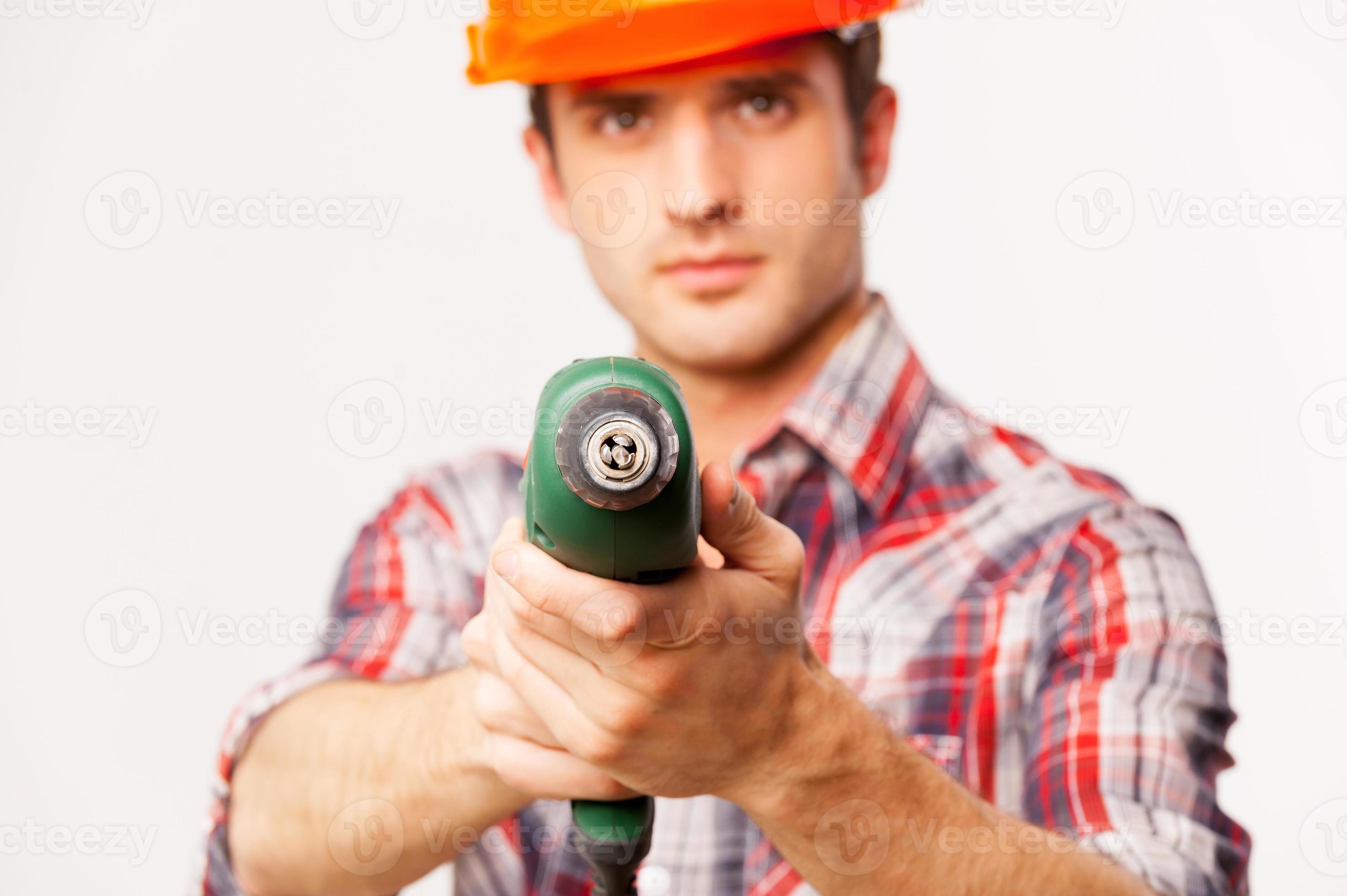 Freeze Handsome young handyman in hardhat stretching out drill and ...
