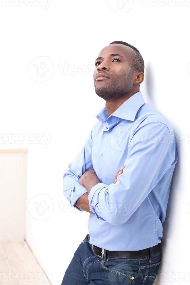 Thoughtful man. Handsome young black man keeping his arms crossed and ...