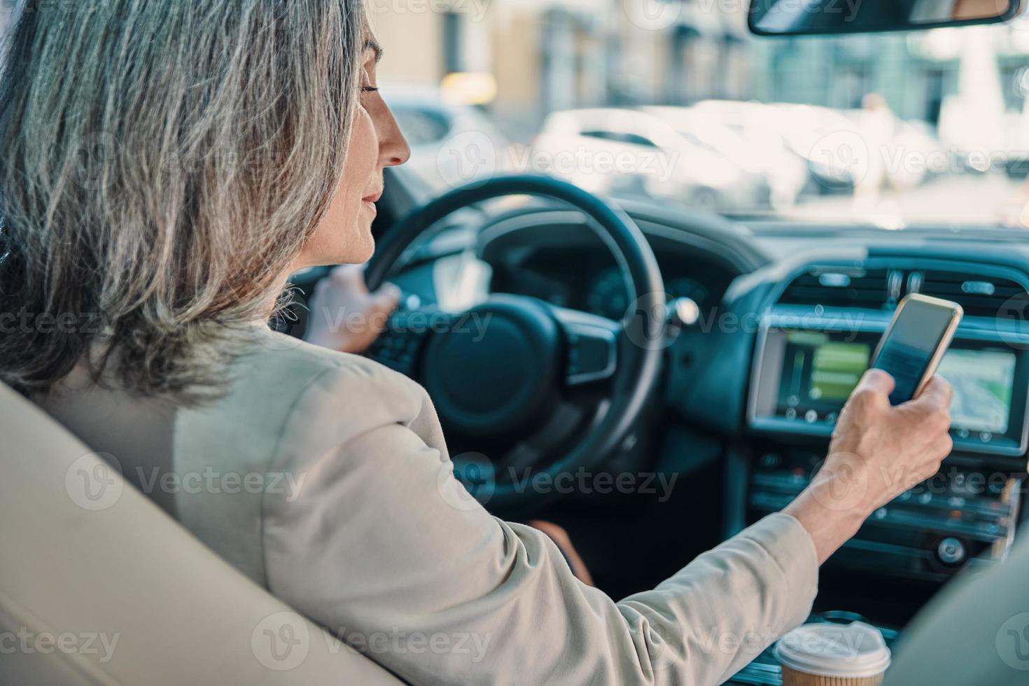Rear view of mature beautiful woman in smart casual wear using phone ...