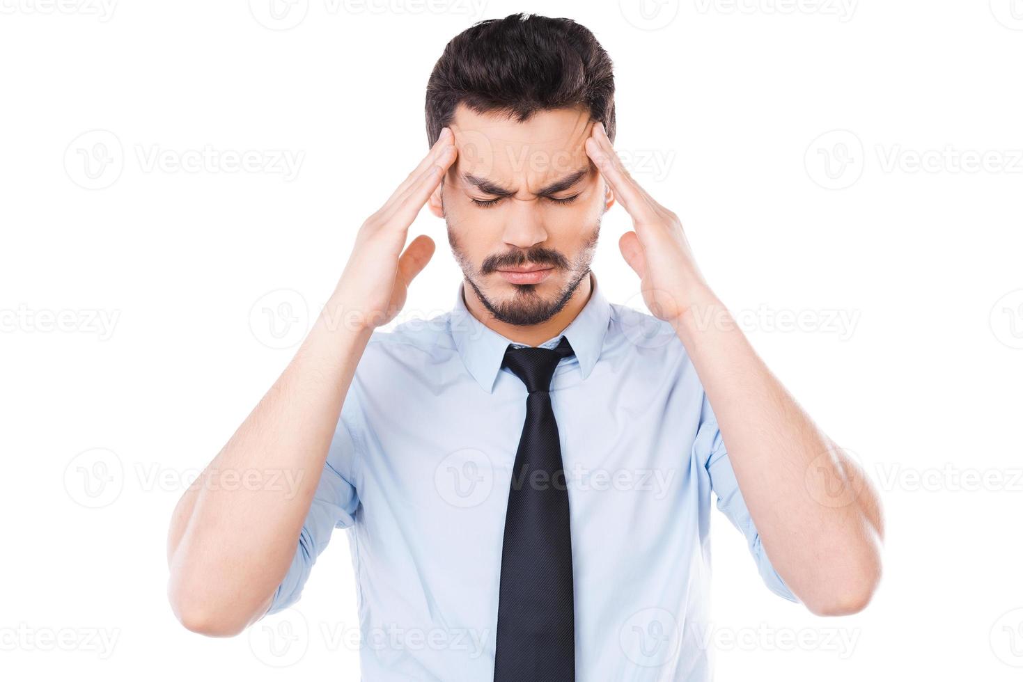 Too much stress. Frustrated young man in shirt and tie touching his head and keeping eyes closed ...