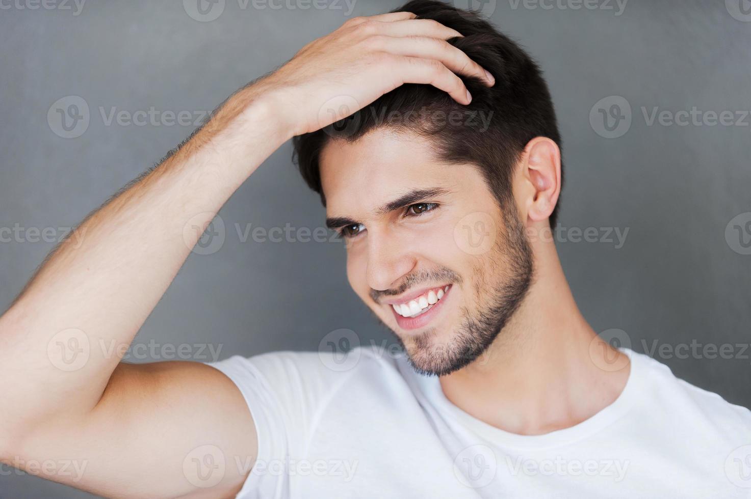 Carefree handsome. Happy young man holding hand in hair and looking ...