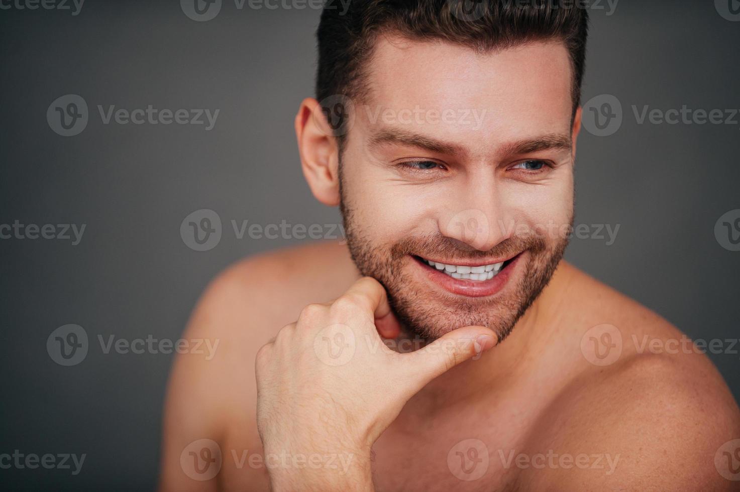 He got candid smile. Confident young shirtless man holding hand on chin ...