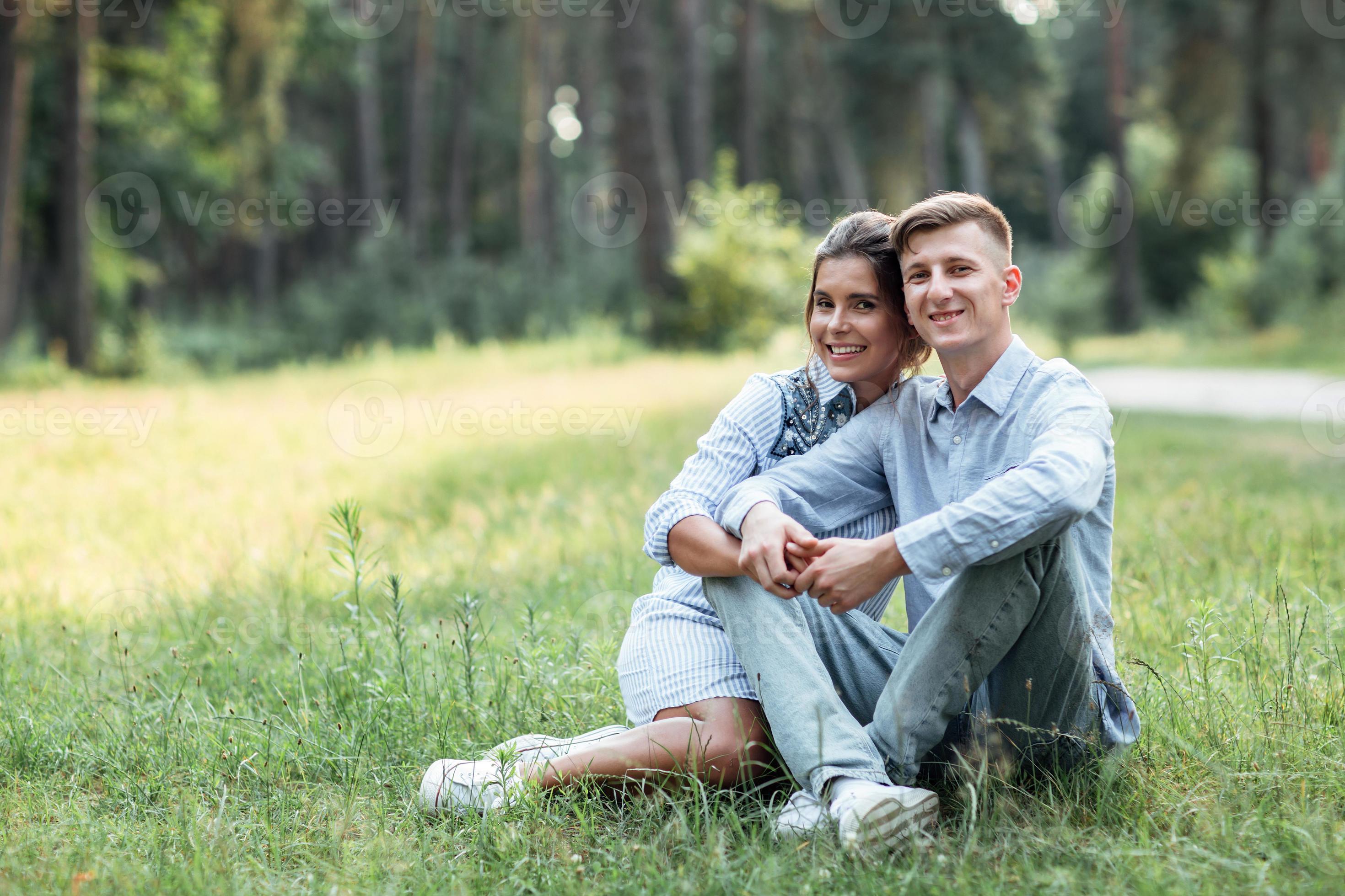 Outdoor Shot Of Young Happy Couple In Love Sitting On Grass On Nature Man And Woman Hugging