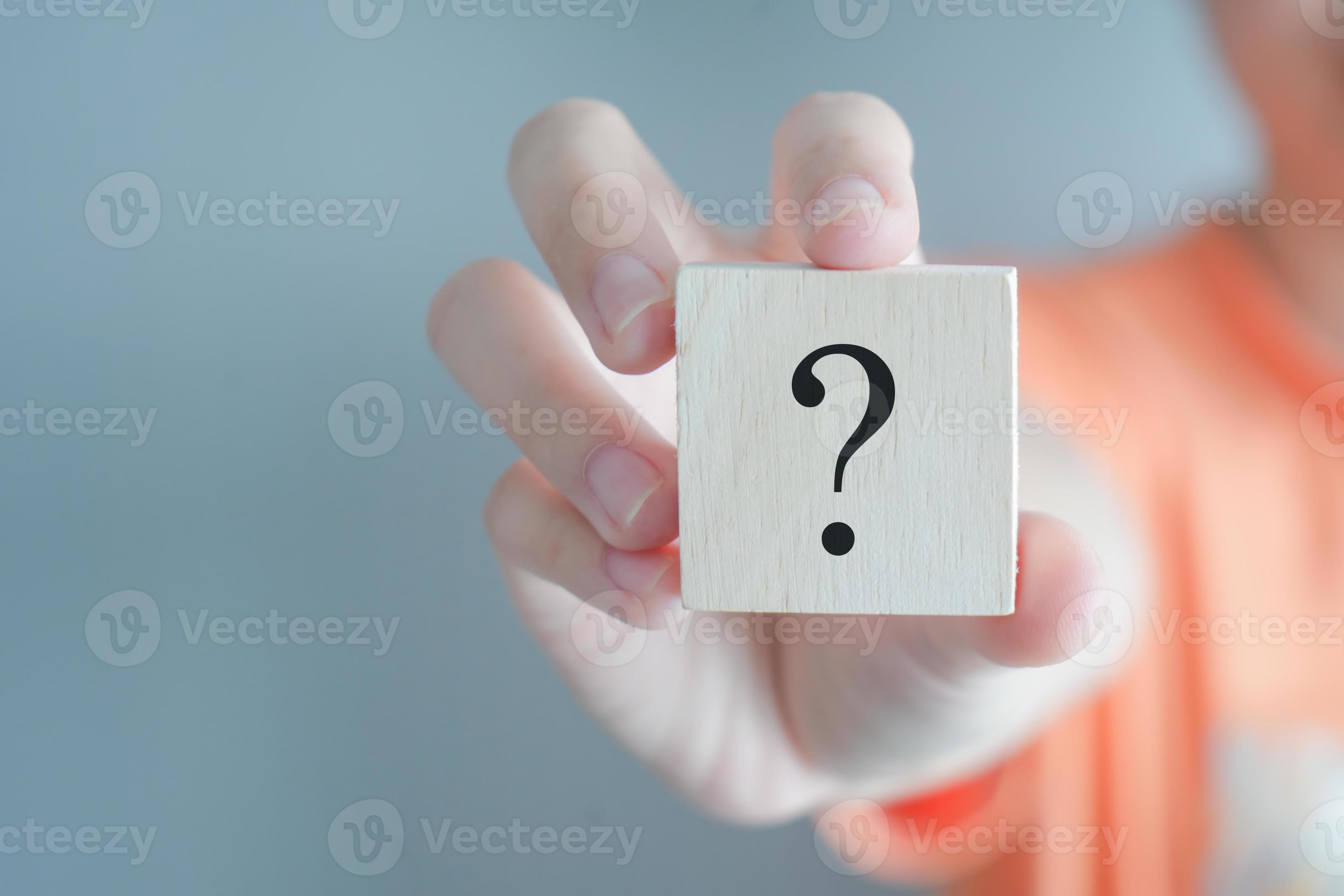 Hand holding question mark symbol on wooden block with copy space. Ask, FAQ, Advice, Support ...