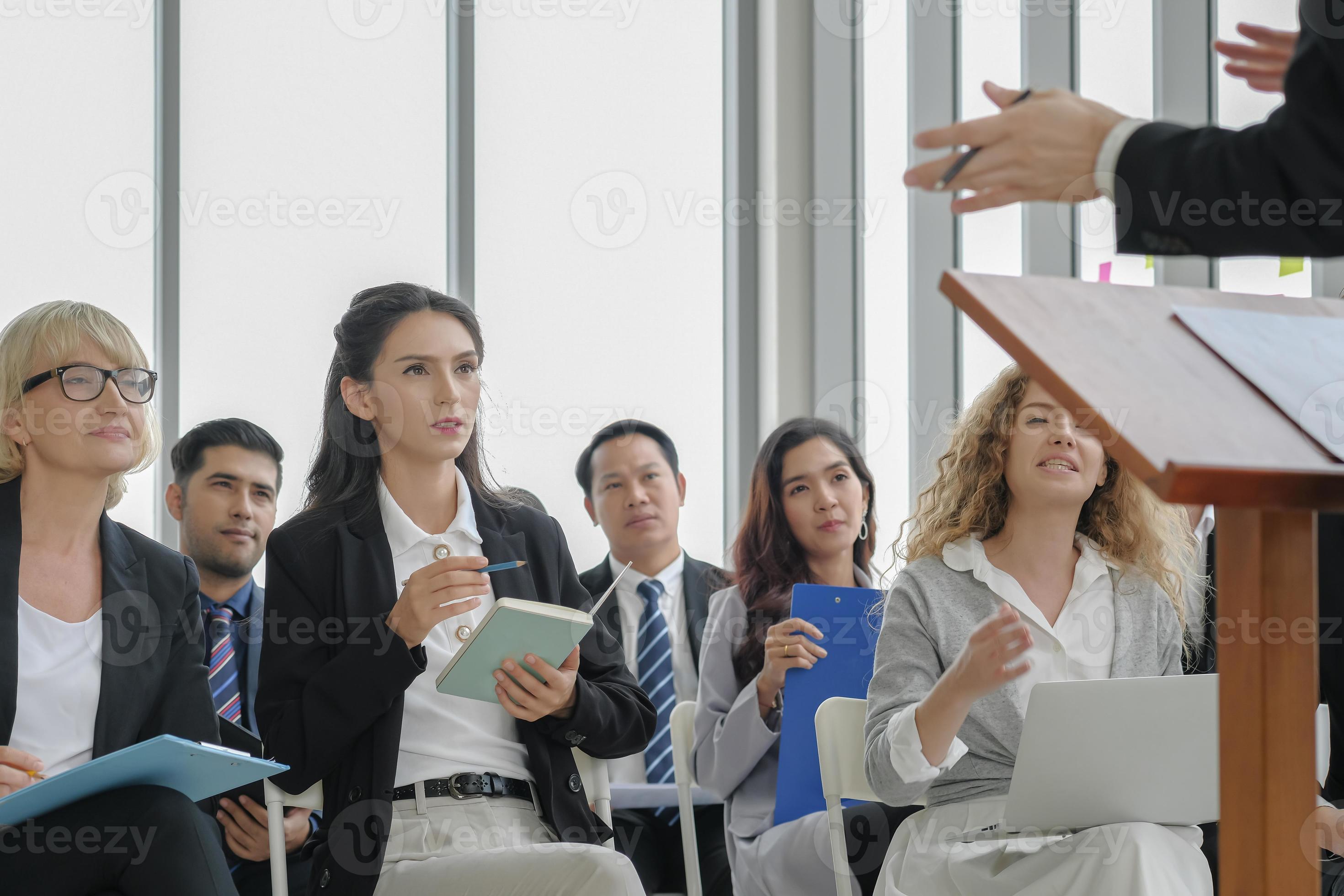 Multi ethnic business audience in corporate attentive listening, take note, asking questions to ...