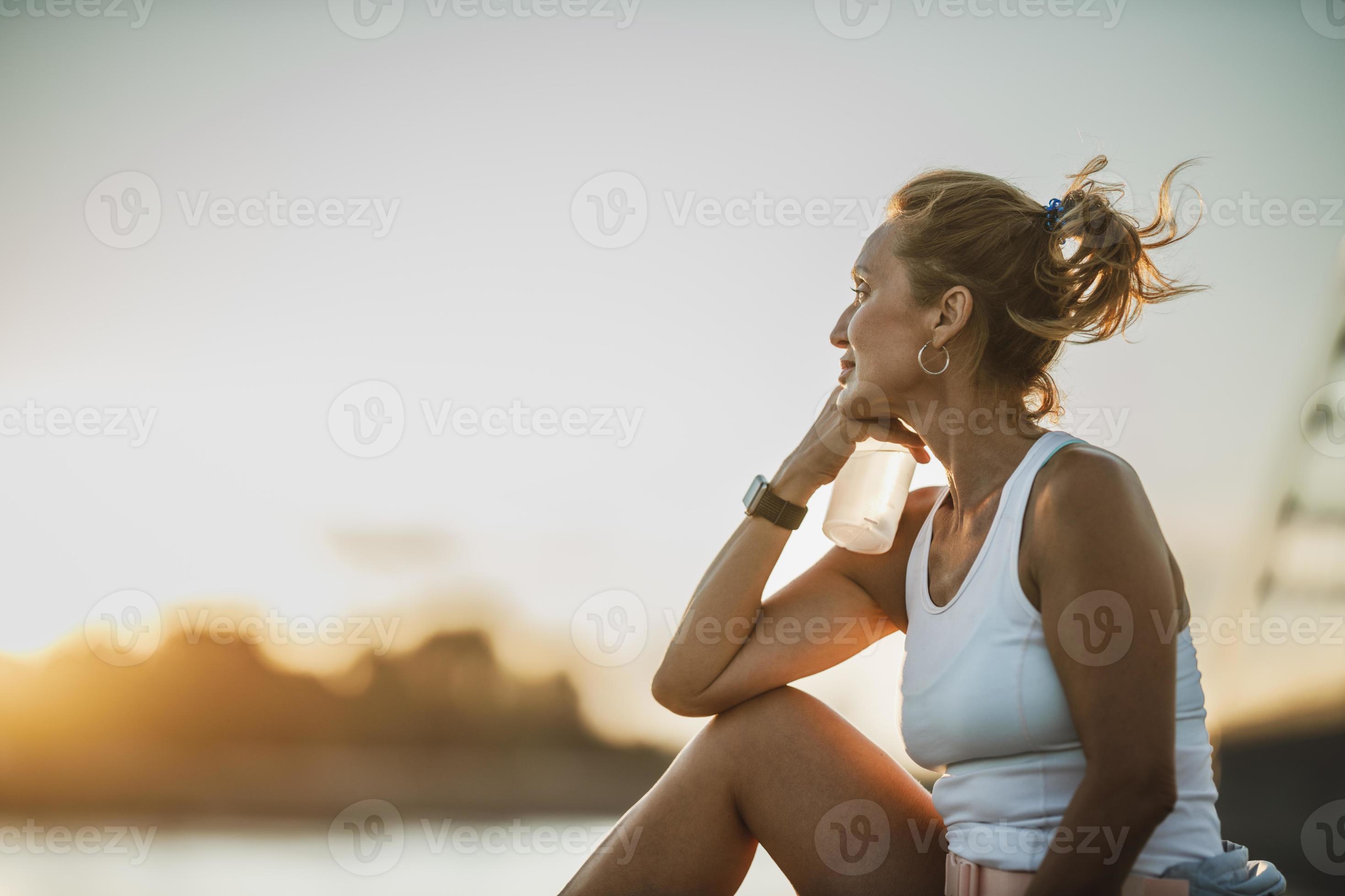 Woman Sitting Near The River And Pensive Looking The Sunrise 14220917 Stock Photo at Vecteezy