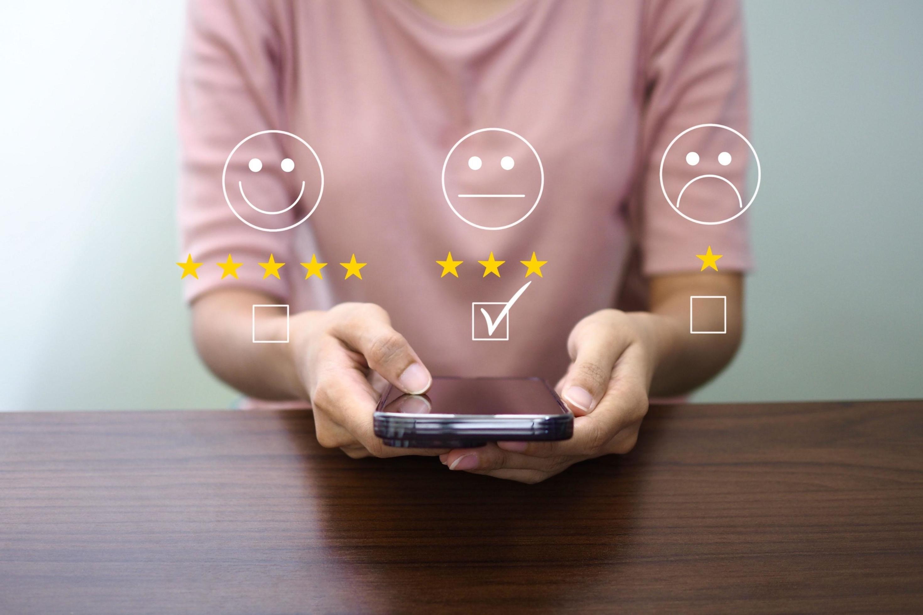 woman holding phone and a sign to choose a smiley face icon to evaluate ... woman holding phone and a sign to choose a smiley face icon to evaluate ...