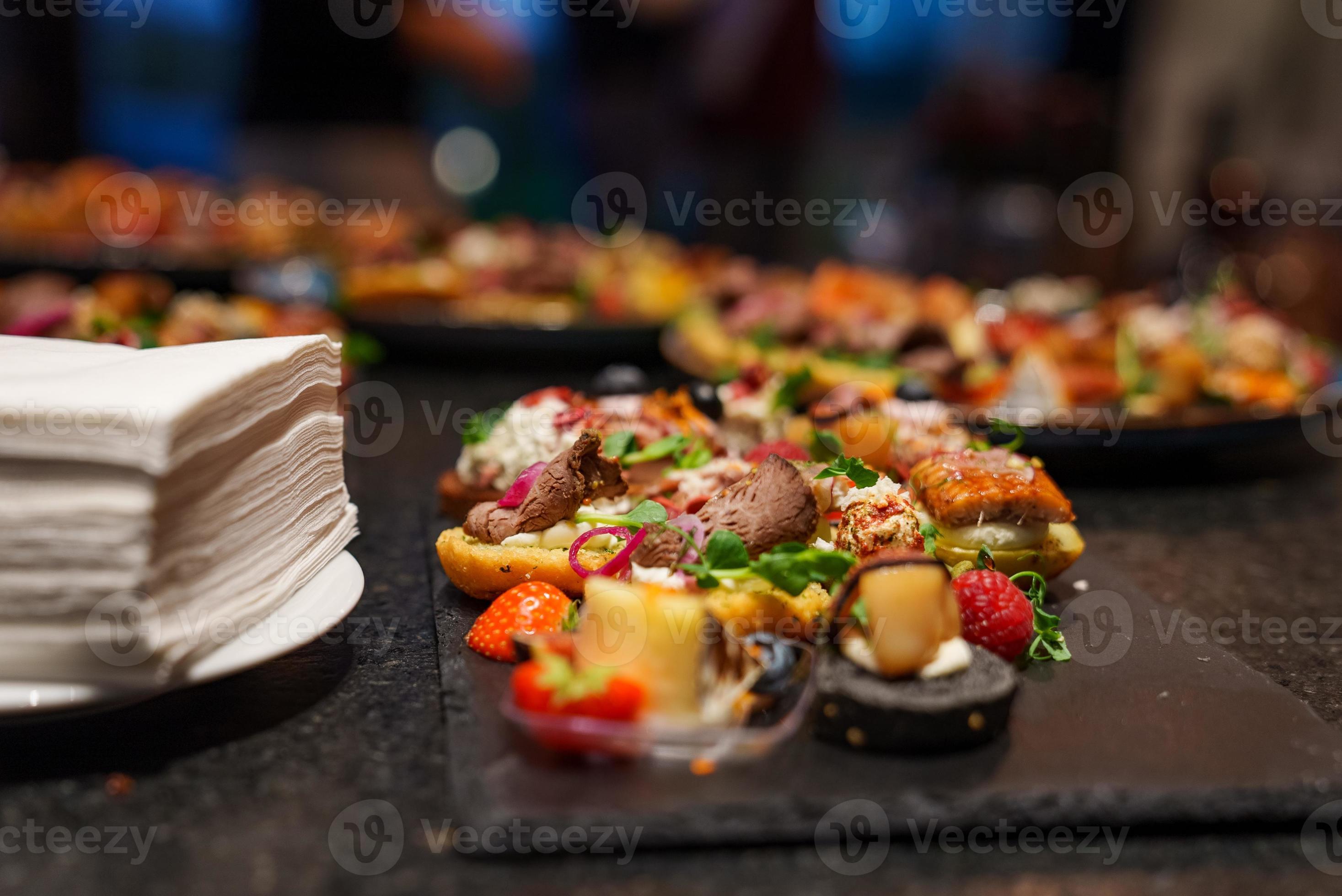 Beautifully decorated catering snacks and appetizers. Set of beautiful canapes on black stone ...