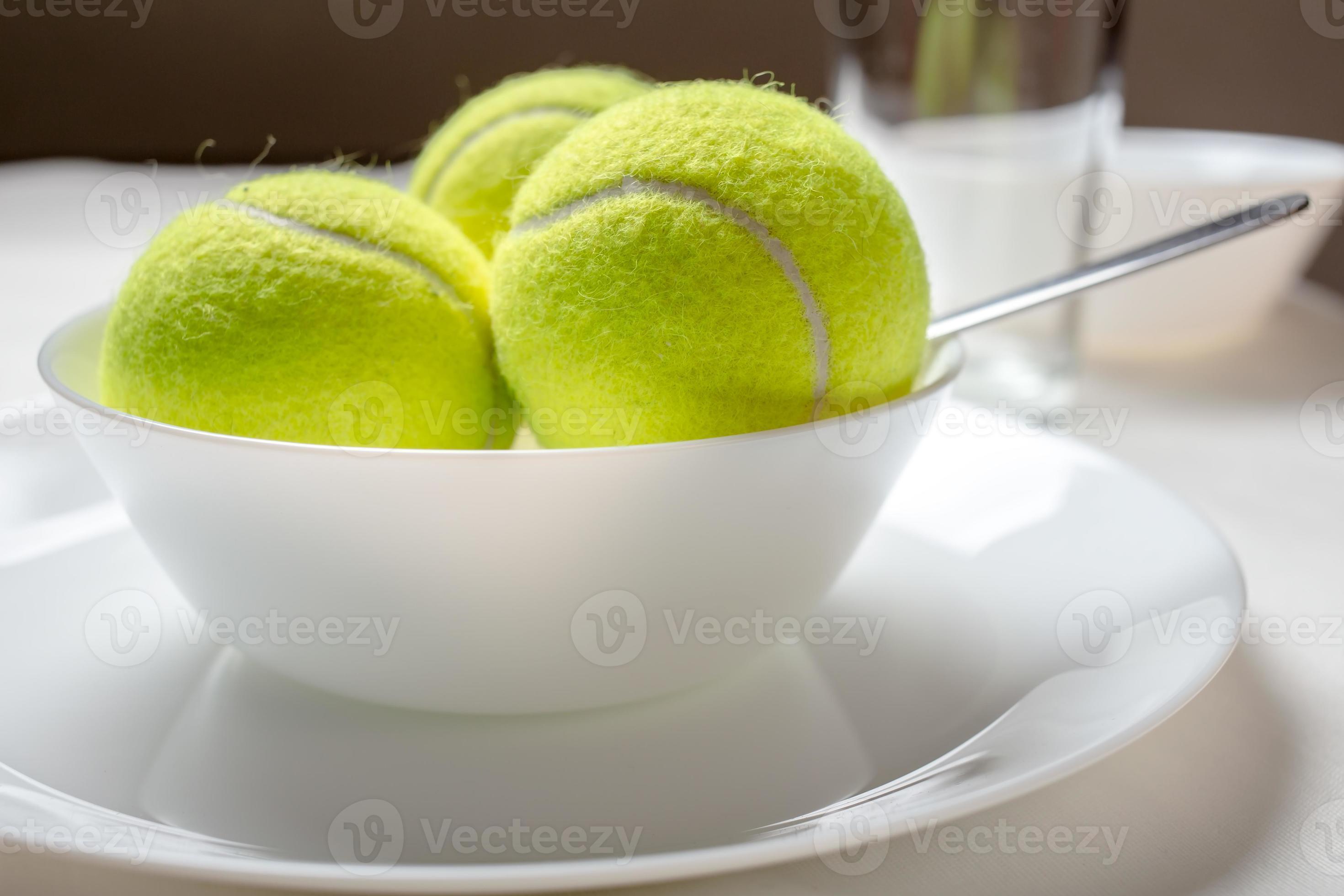 Yellow tennis balls in a bowl instead of ice cream, against a dark background. Concept of proper ...