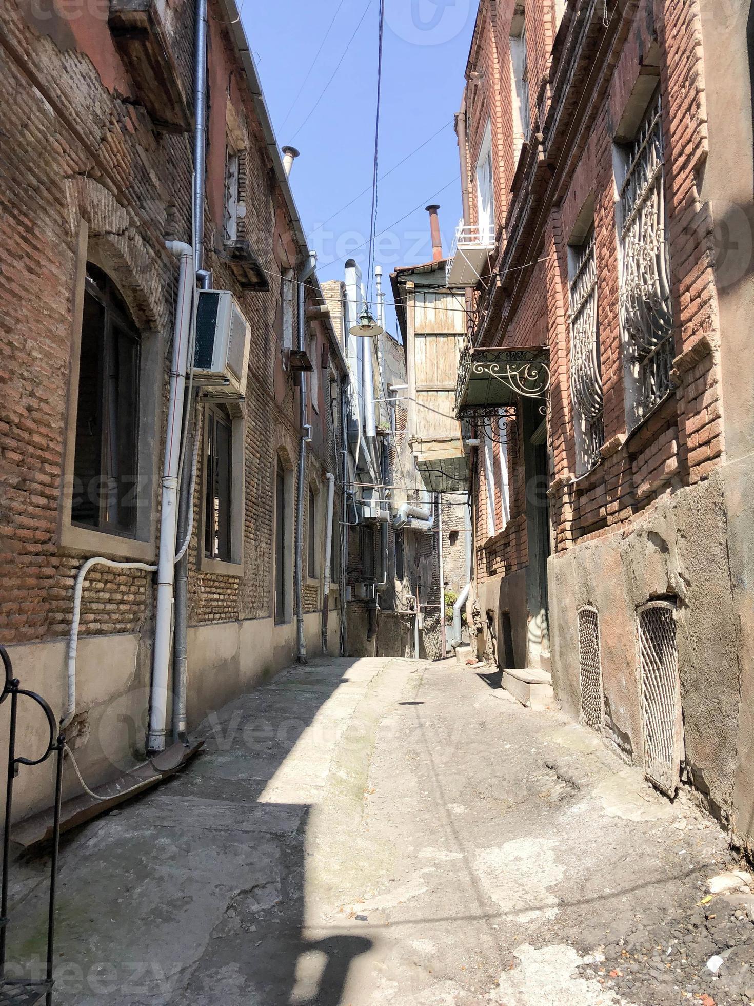 Narrow street, lane, tunnel with old houses, buildings on the sides in a poor area of the city ...