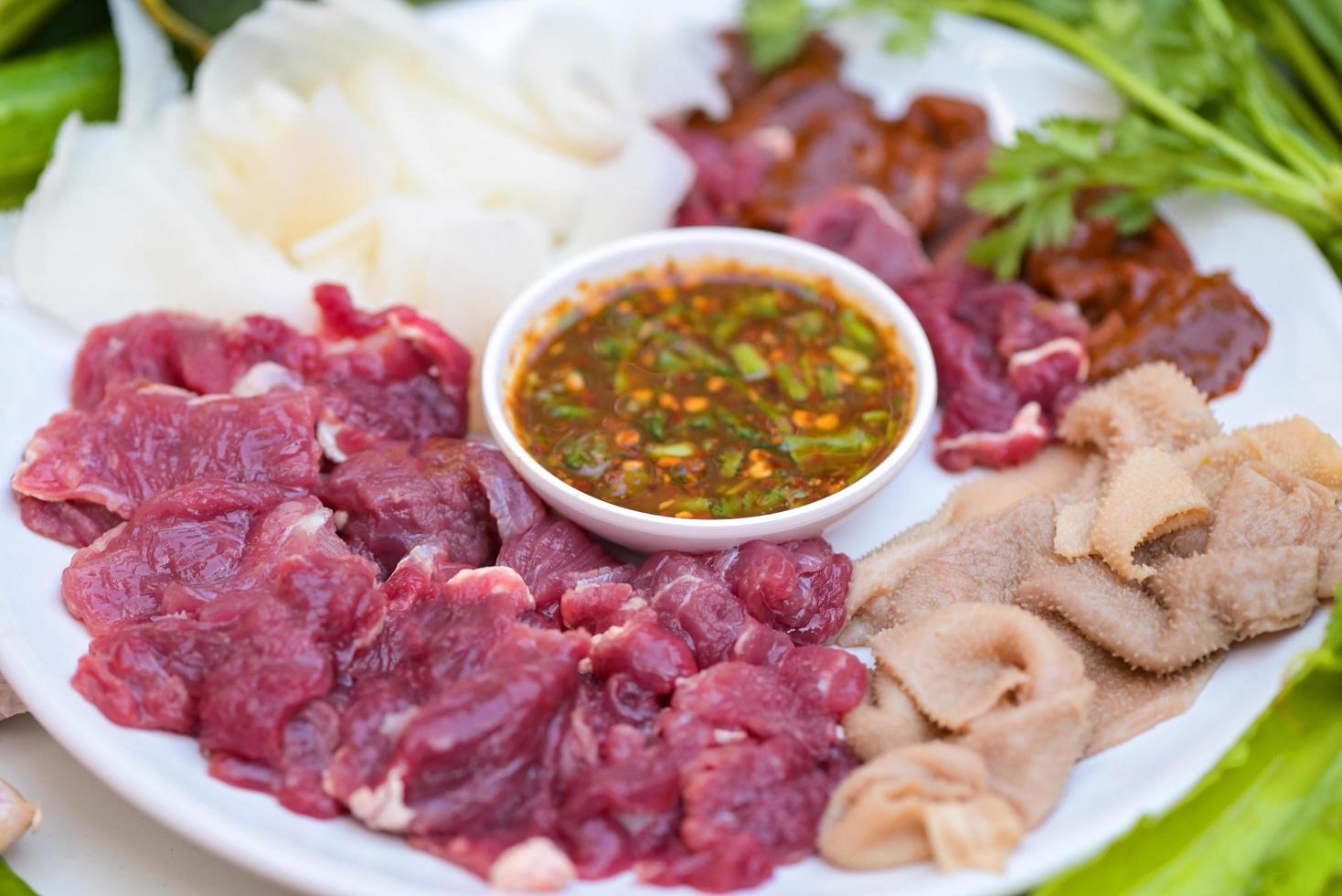 beef sashimi meat - raw beef slice on plate with fresh vegetables and spicy sauce, Thai food ...