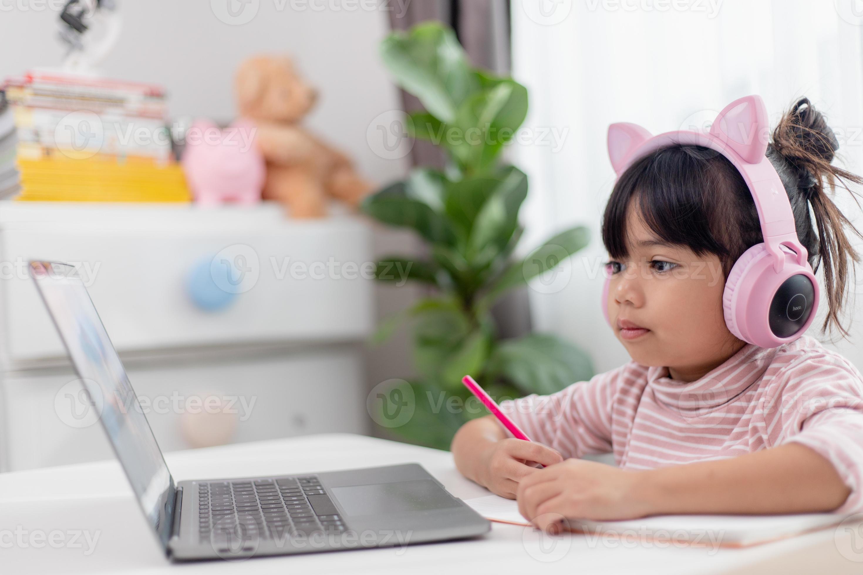 Asian little girl in headphones have video call distant class with teacher using laptop, study ...