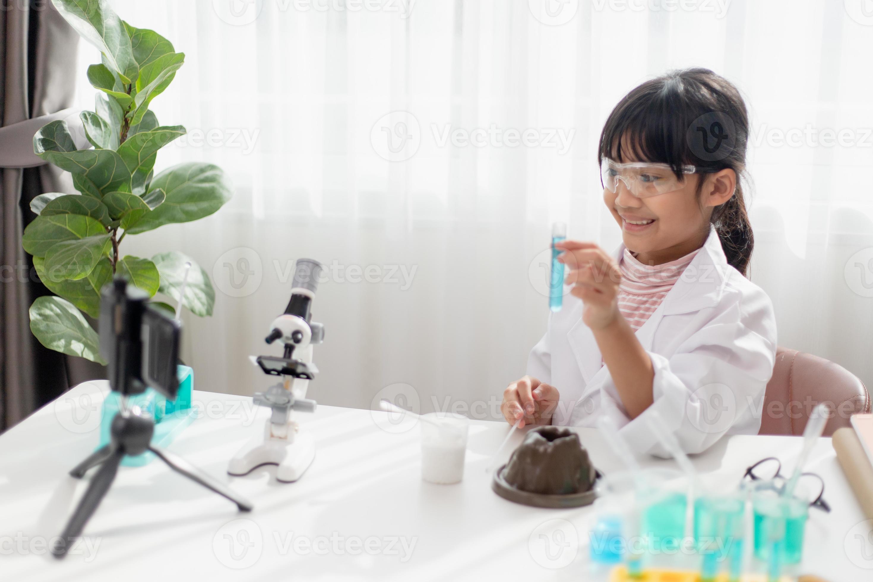 Asian school girl making easy chemistry experiments and recording a video for his followers ...