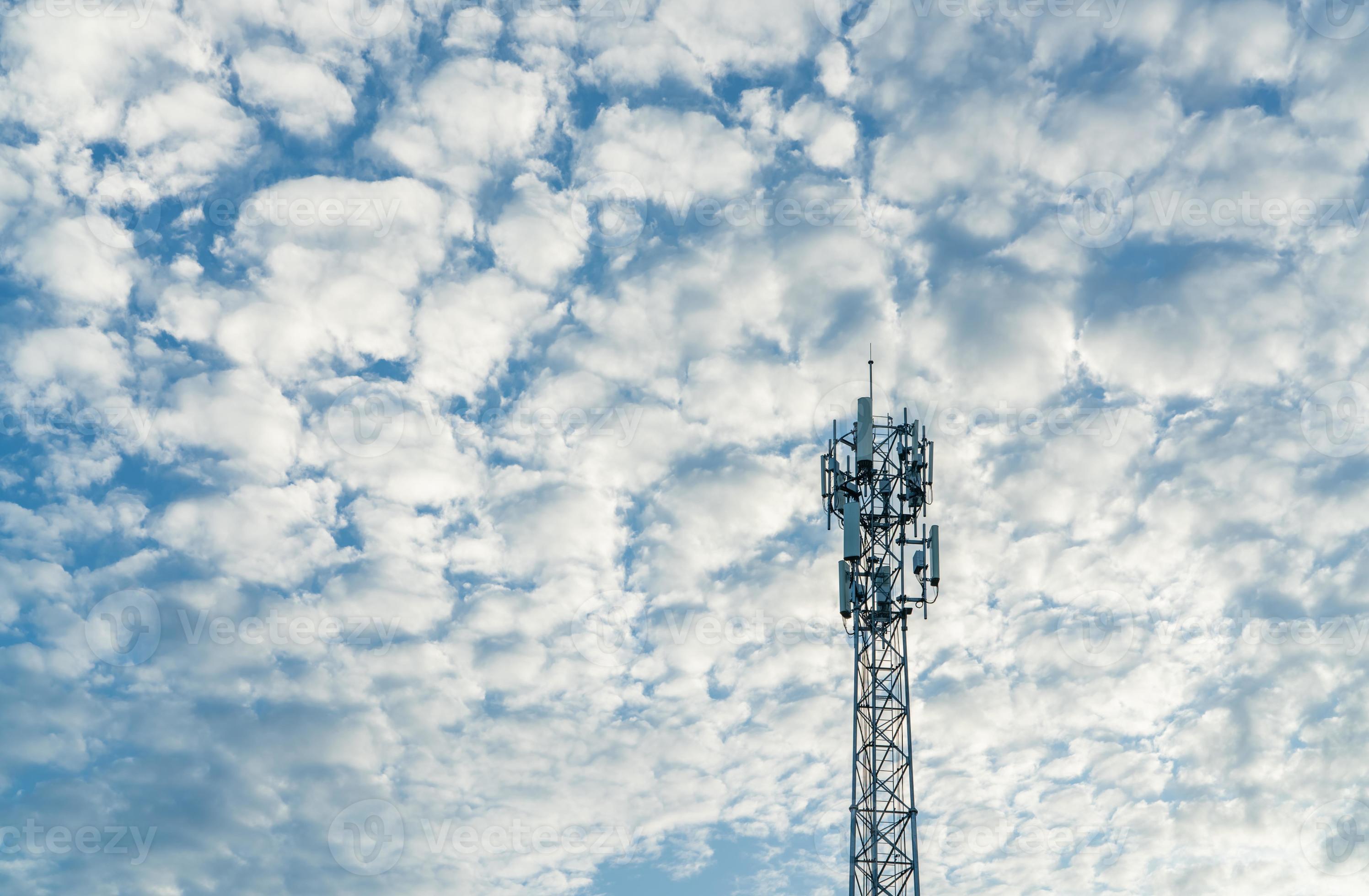 Telecommunication tower with blue sky and white clouds background. Antenna on blue sky. Radio ...