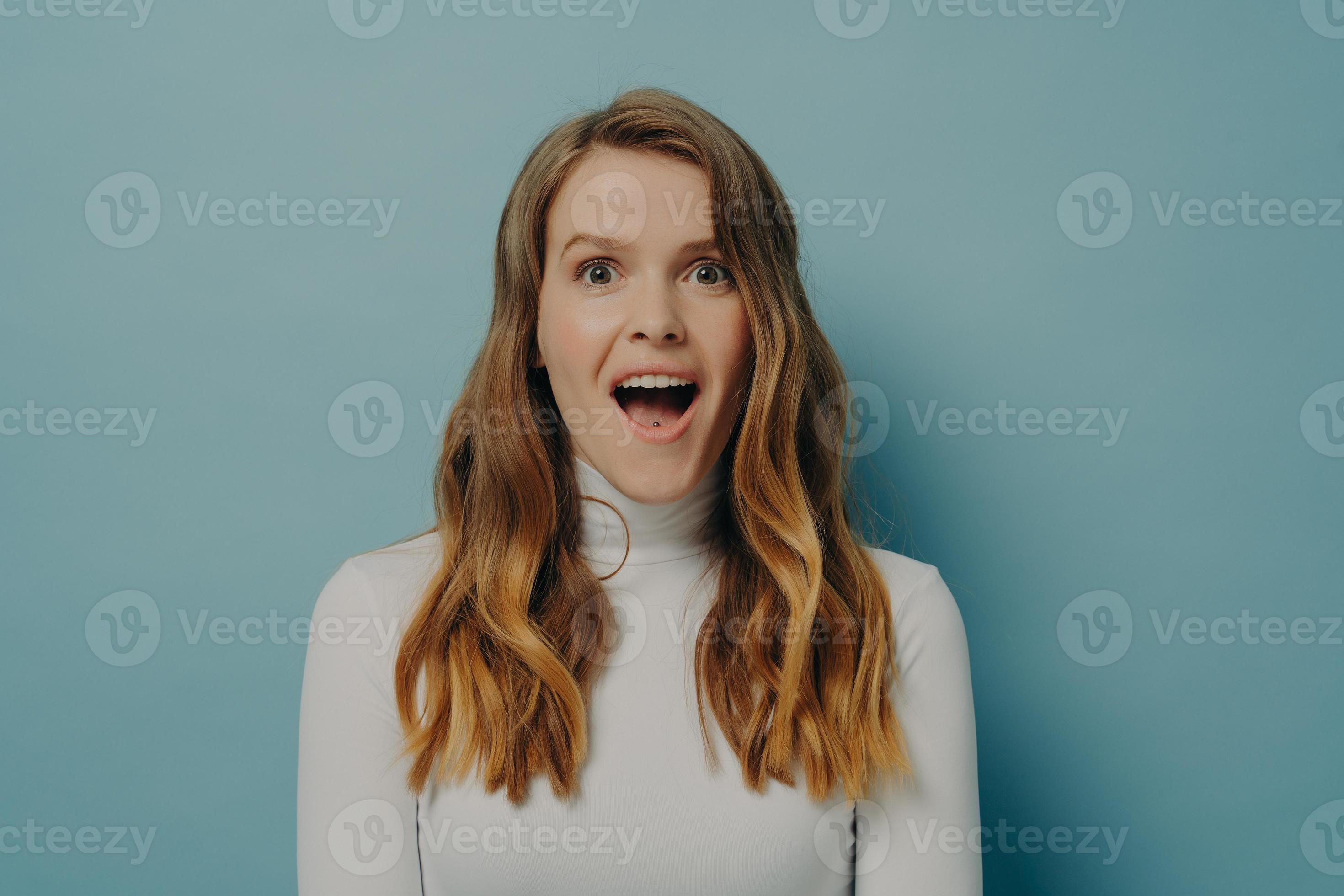 Amazed Young Woman With Surprised Funny Facial Expression Looking At Camera With Mouth Wide Open
