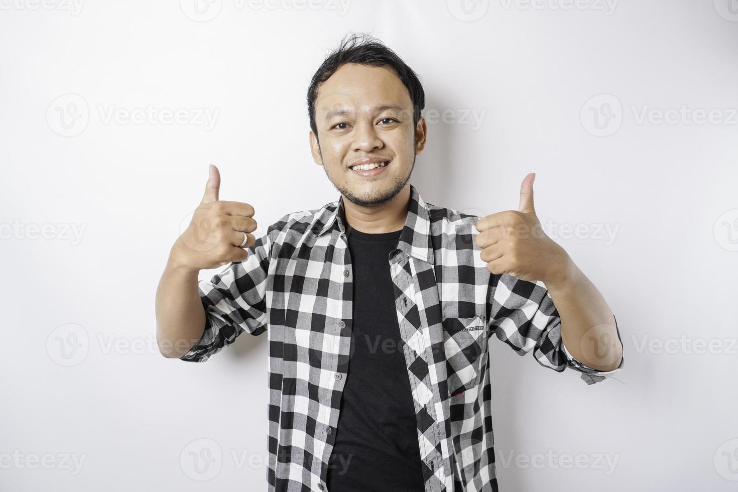 Excited Asian man wearing tartan shirt gives thumbs up hand gesture of ...