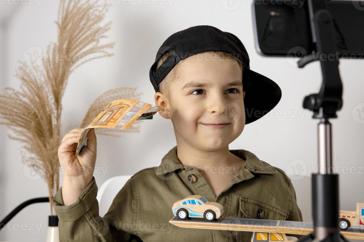 Adorable, cute, little boy blogger recording lifestyle blog, talking to camera of smartphone on ...