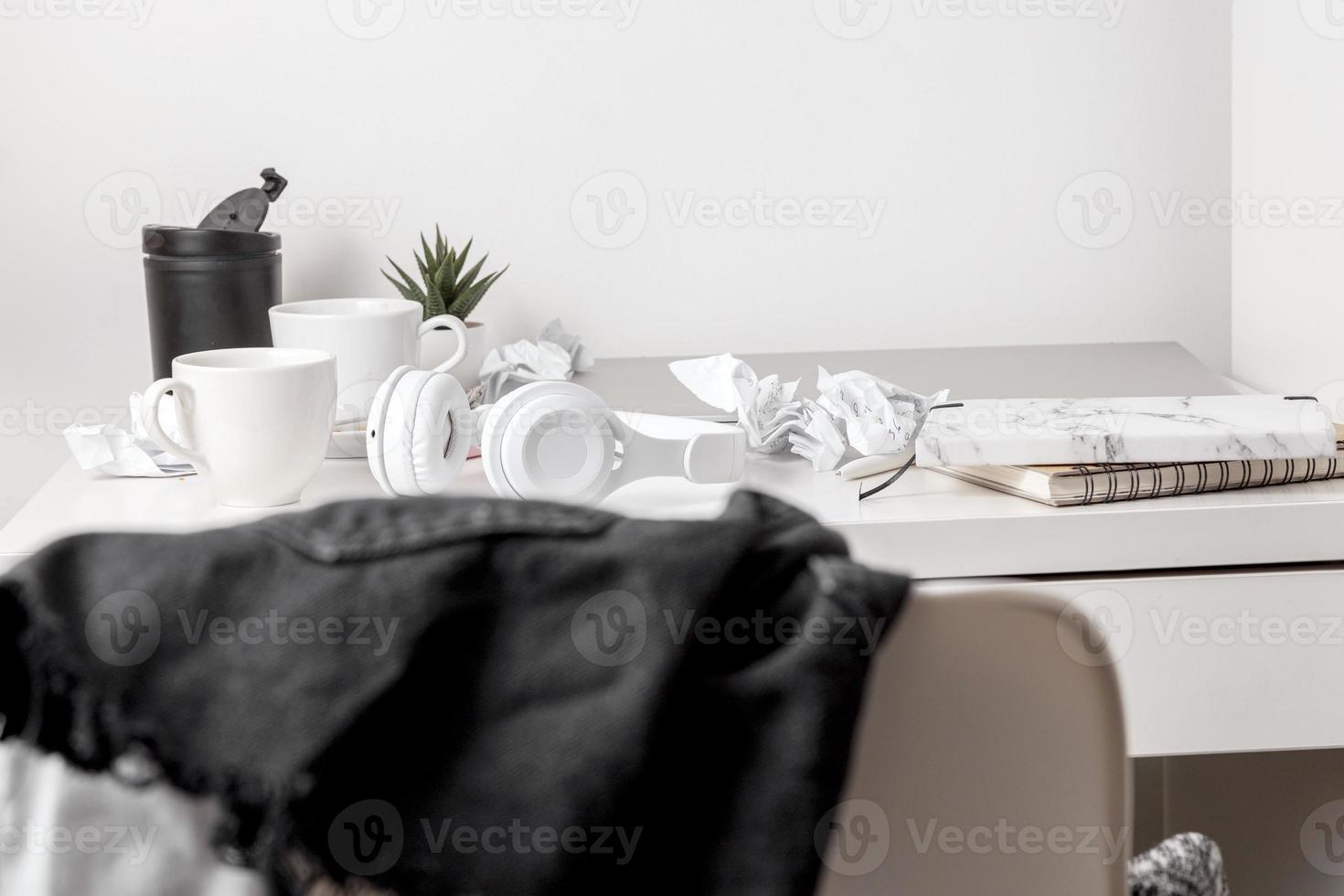 Messy table with laptop, dirty cups, and stationary items. Cluttered ...