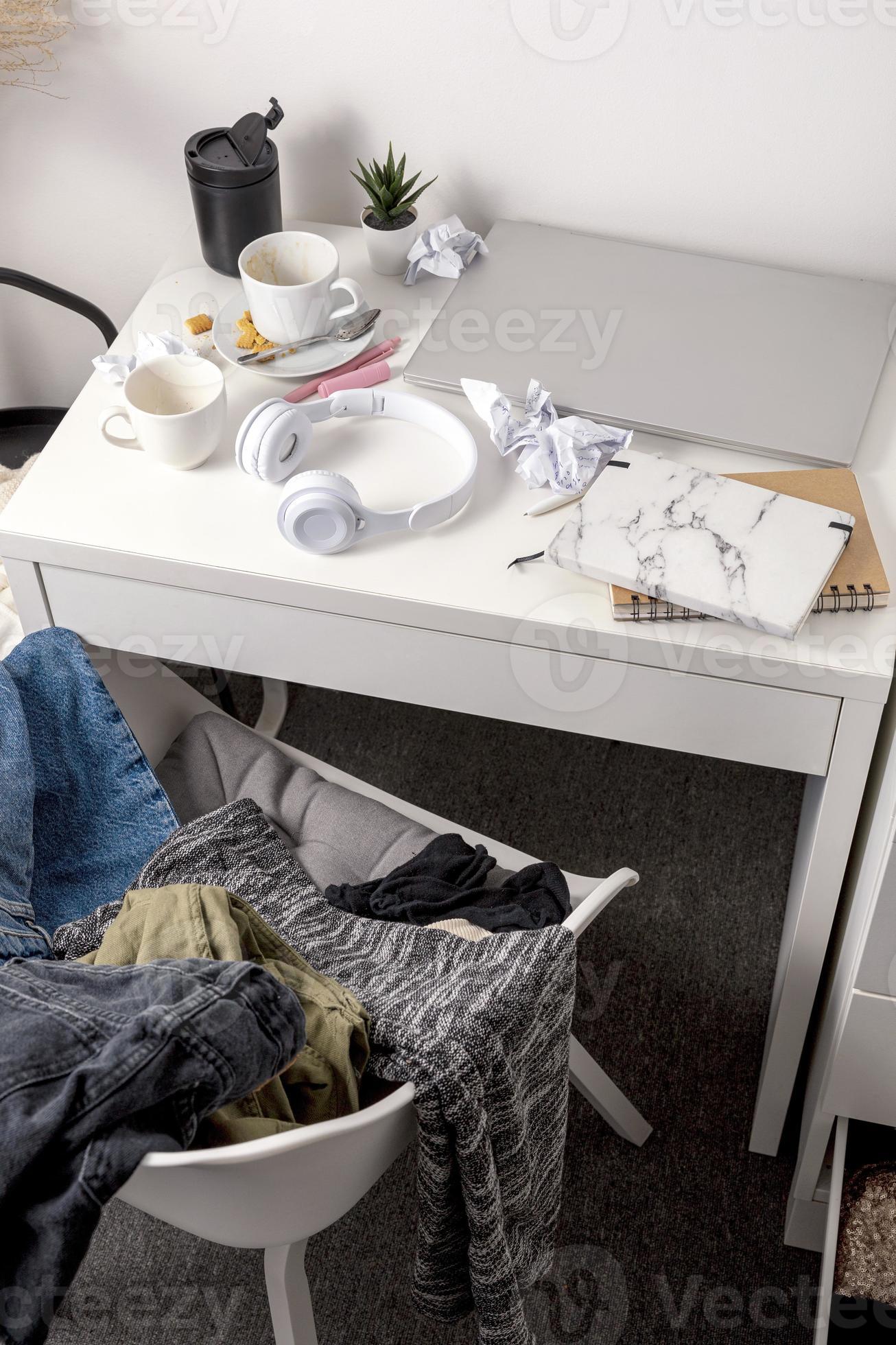 Messy table with laptop, dirty cups, and stationary items. Cluttered ...