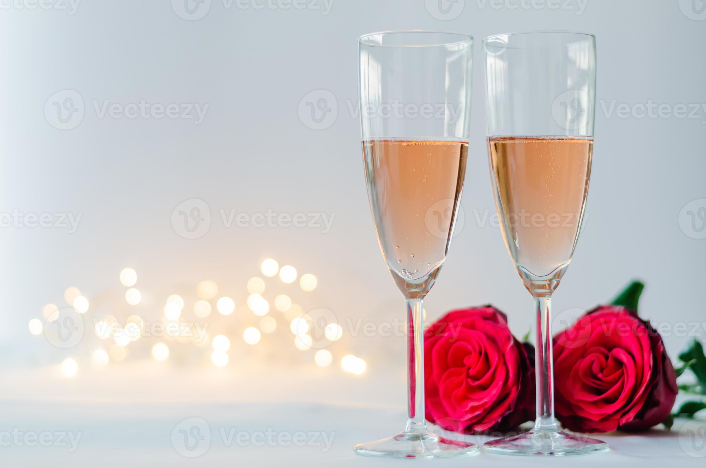 Glasses Of Sparkling Rose Wine With Red Roses On White Background With Bokeh Light For