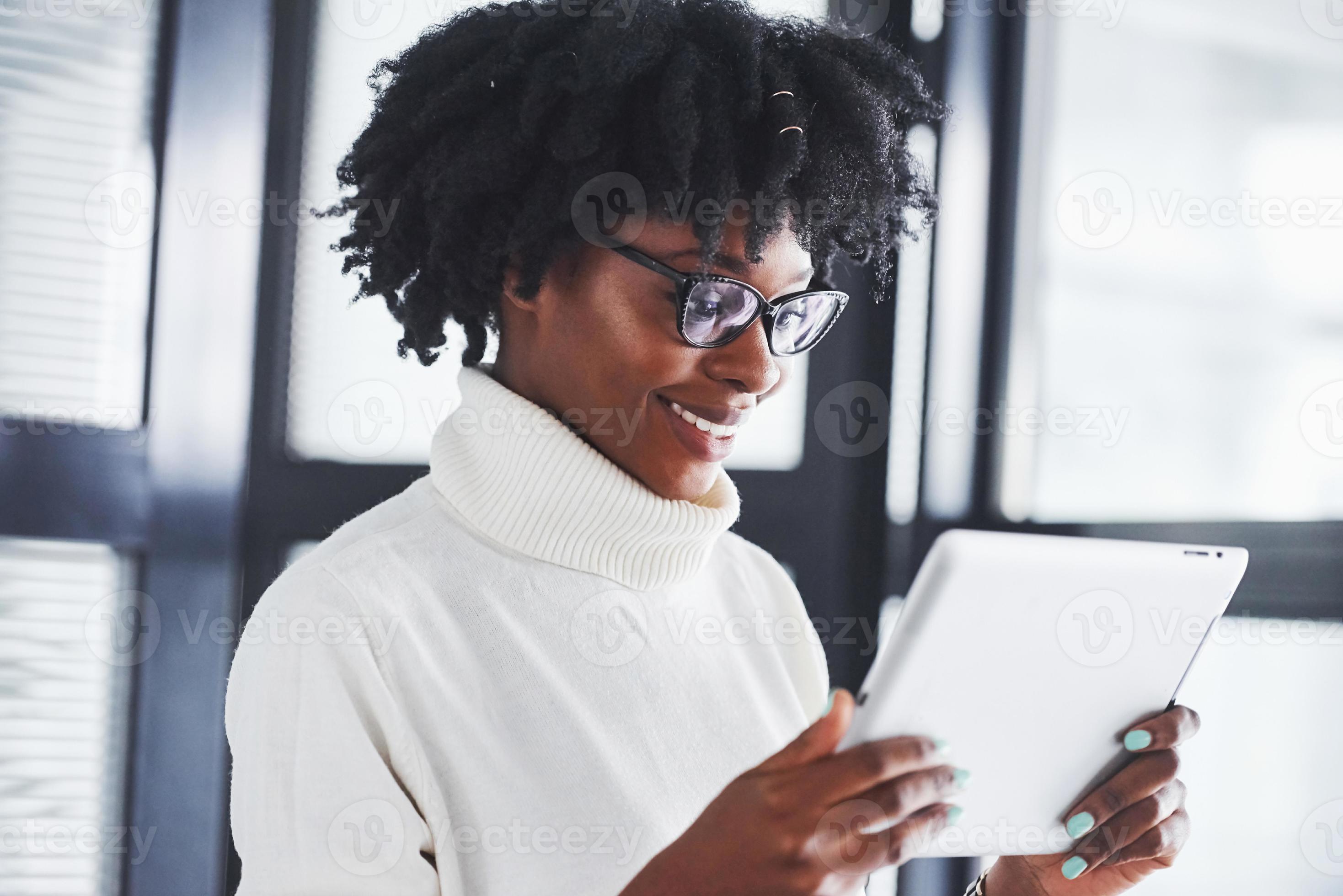 Young african american woman in glasses stands indoors in the office ...