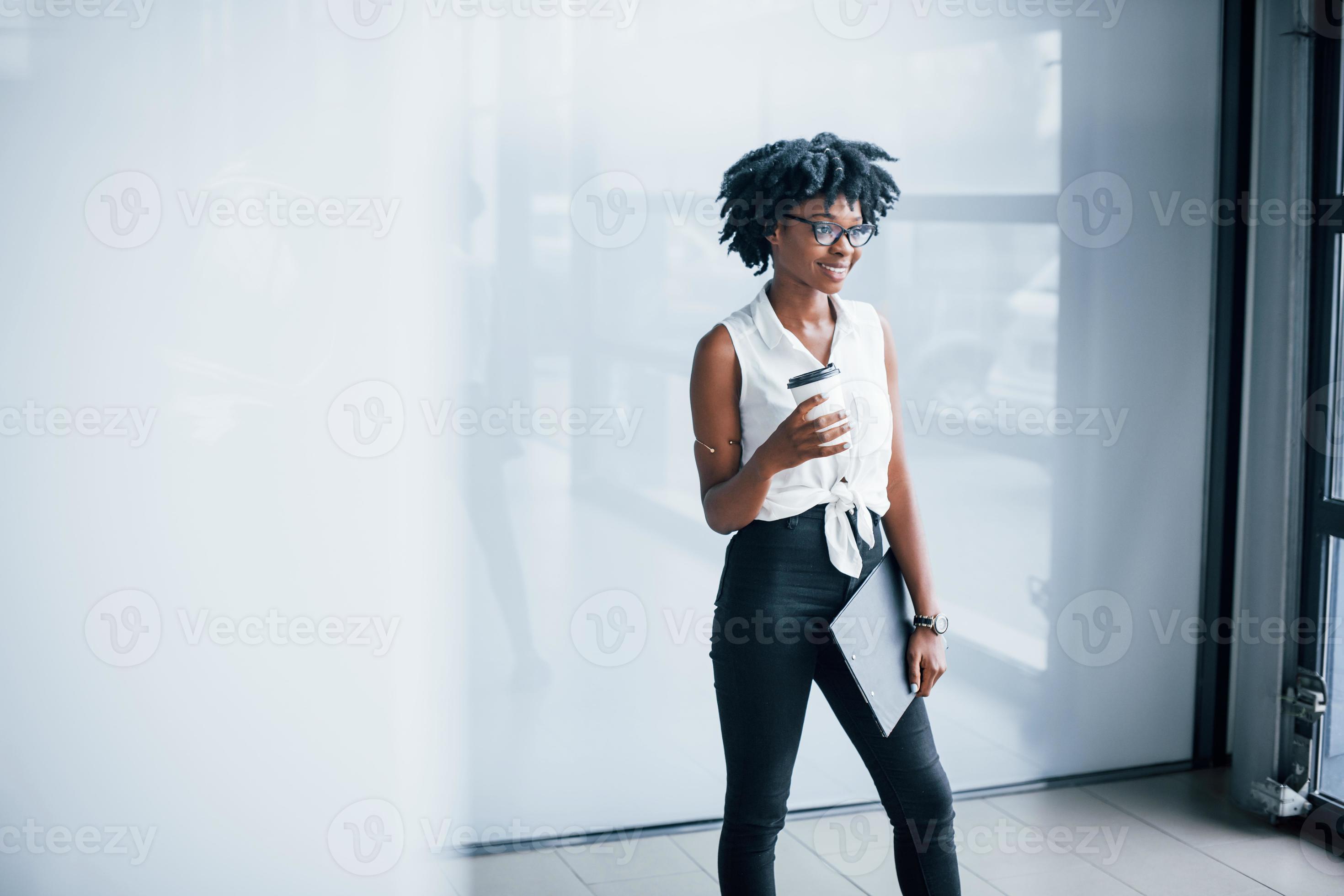 Young african american woman in glasses stands indoors in the office ...