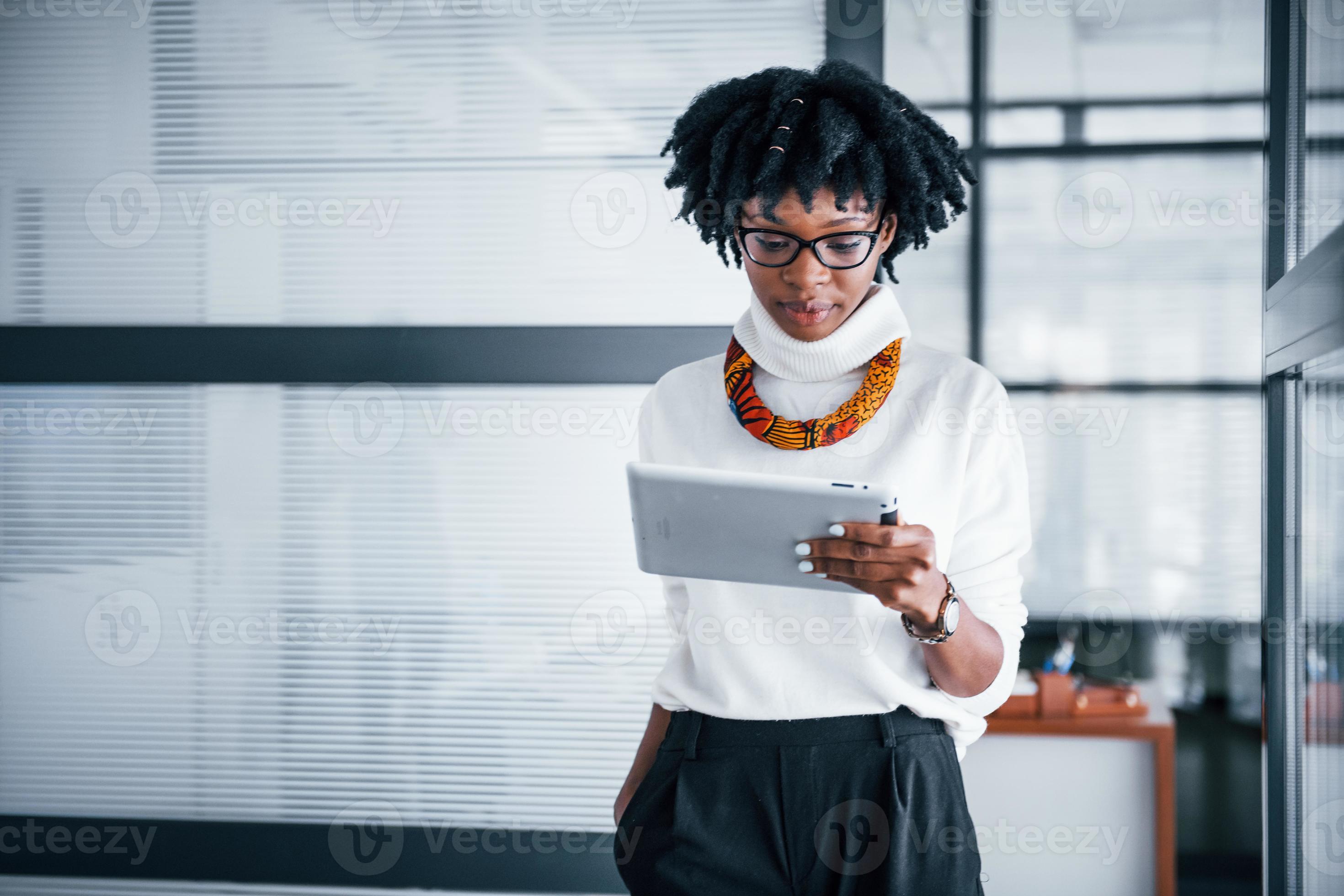 Young african american woman in glasses stands indoors in the office ...