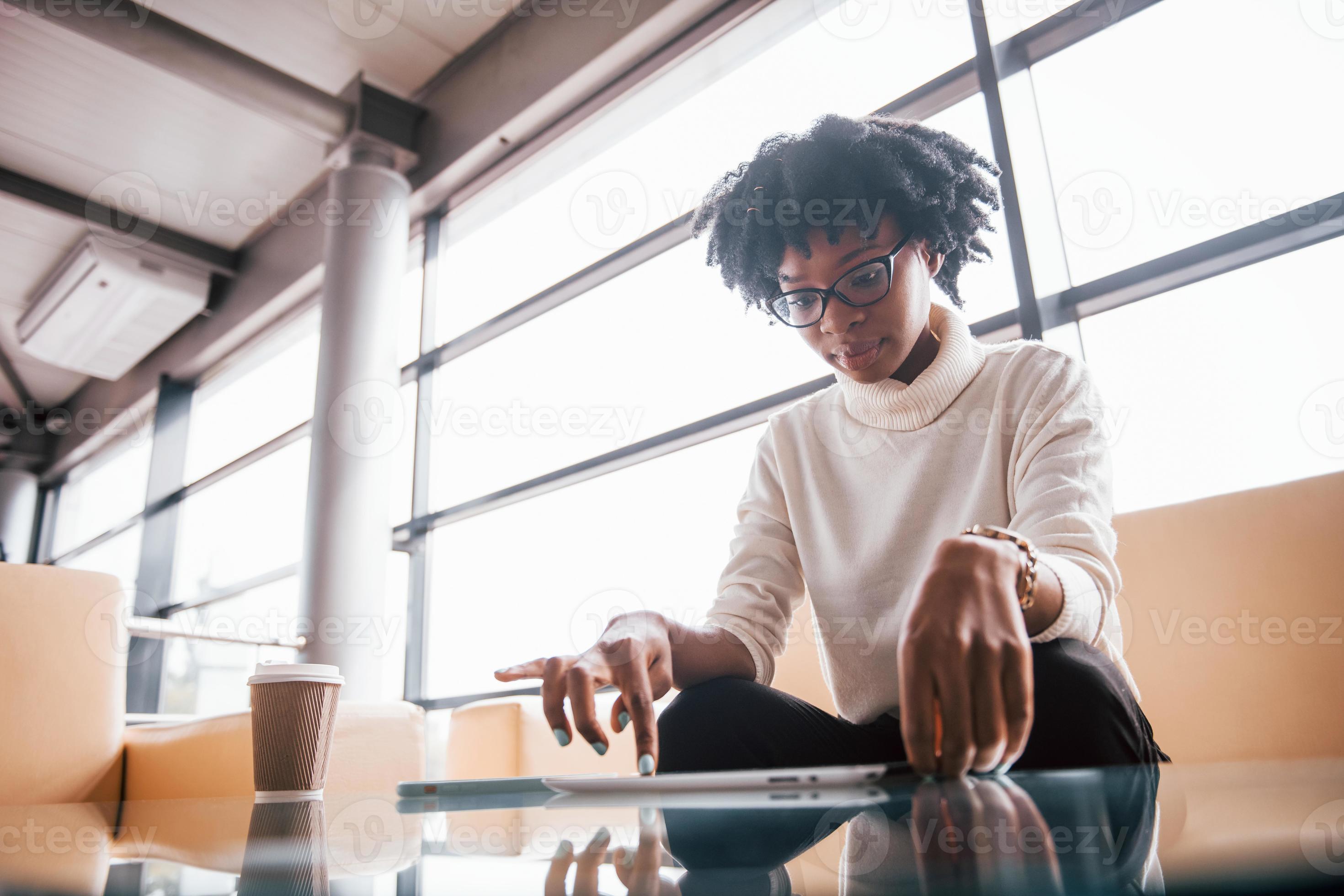 Young african american woman in glasses sits indoors in the office with ...