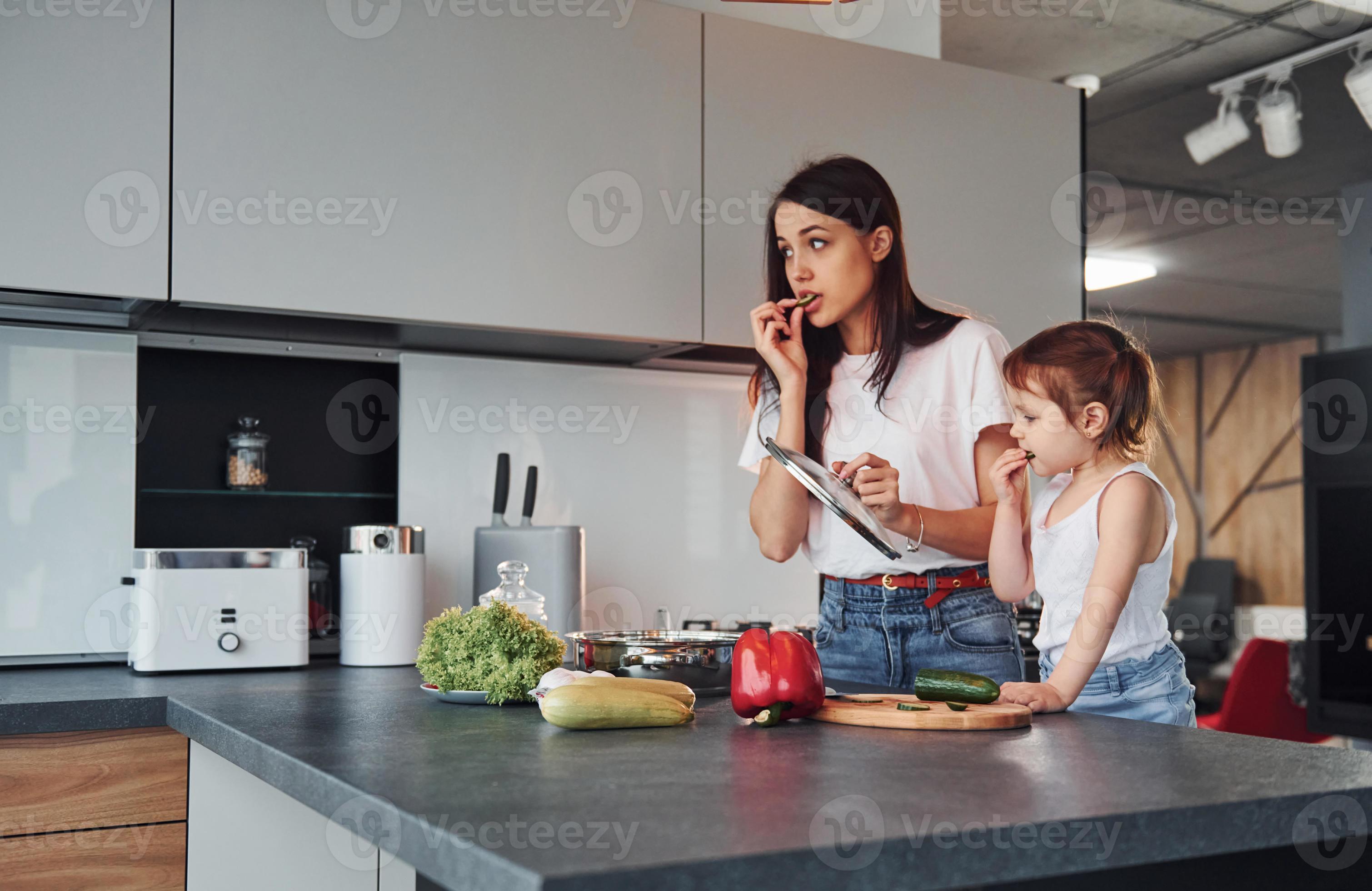 Mother teaching her little daughter preparing food indoors in kitchen ... Mother teaching her little daughter preparing food indoors in kitchen ...
