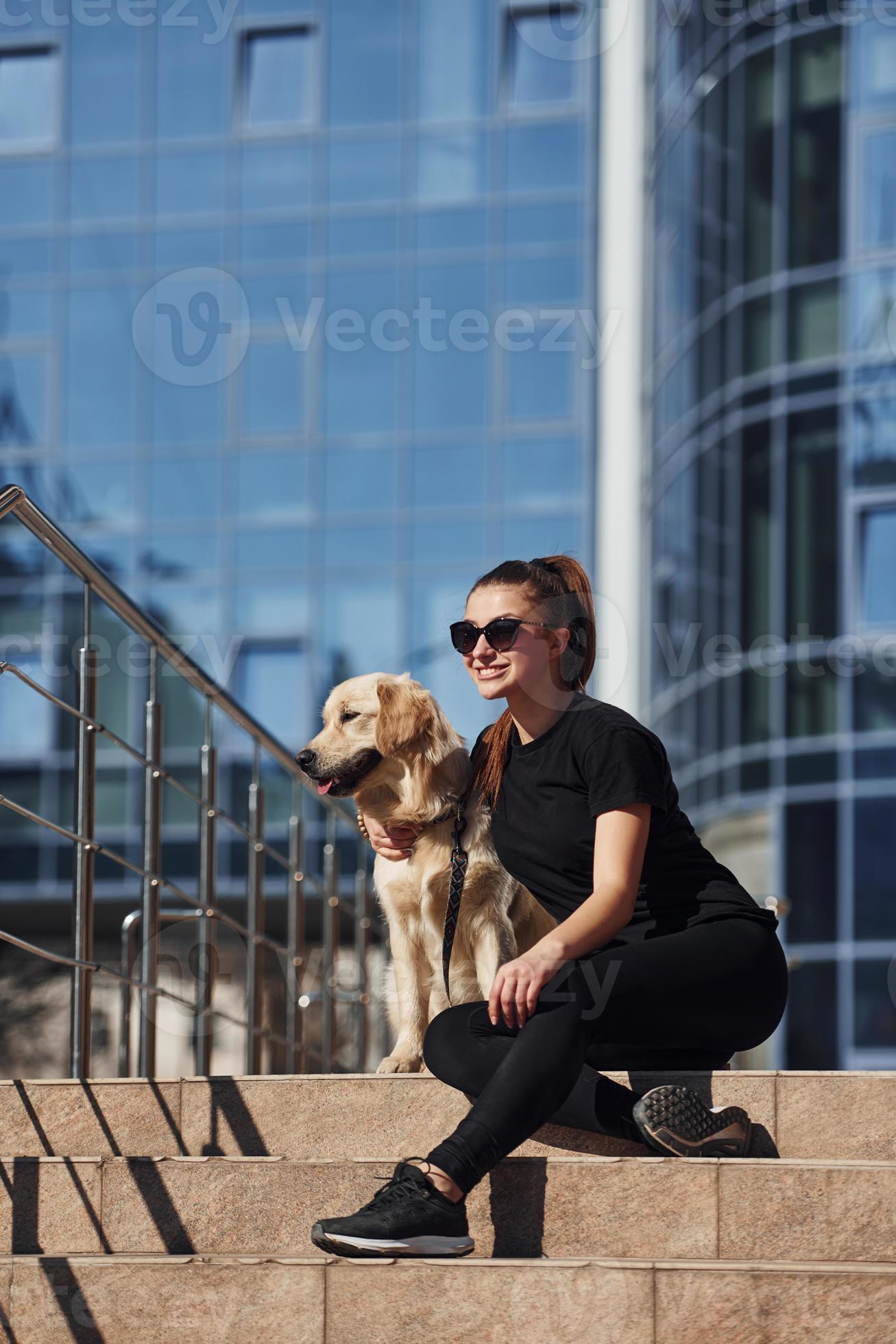 Young positive woman sitting on stairs with her dog when have a walk ... Young positive woman sitting on stairs with her dog when have a walk ...