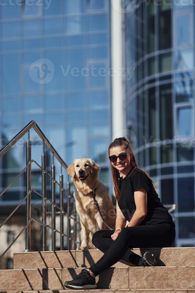 Young positive woman sitting on stairs with her dog when have a walk ... Young positive woman sitting on stairs with her dog when have a walk ...