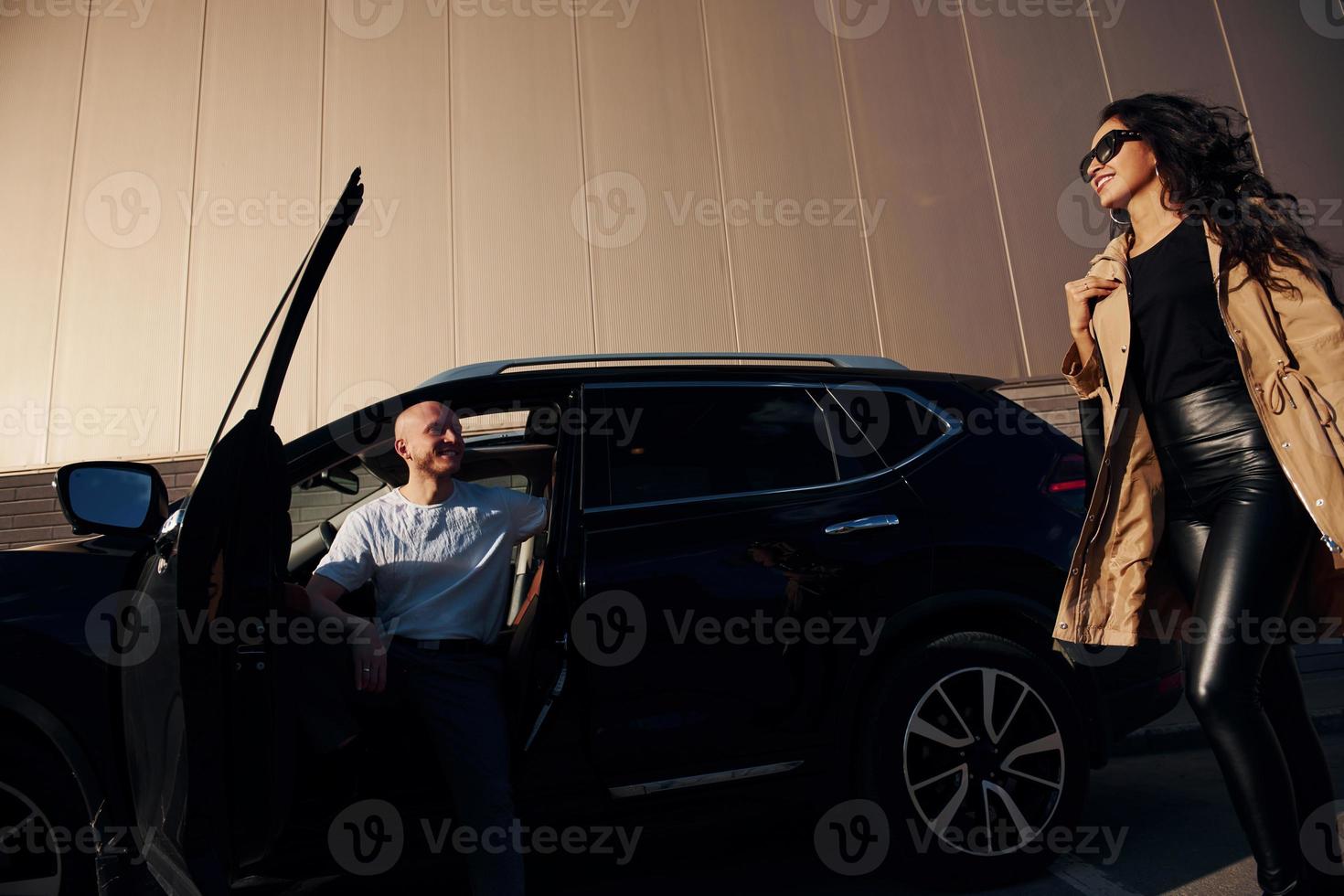 Man At Background Young Woman In Black Leggins Walks Out From Her Modern Car 15288149 Stock